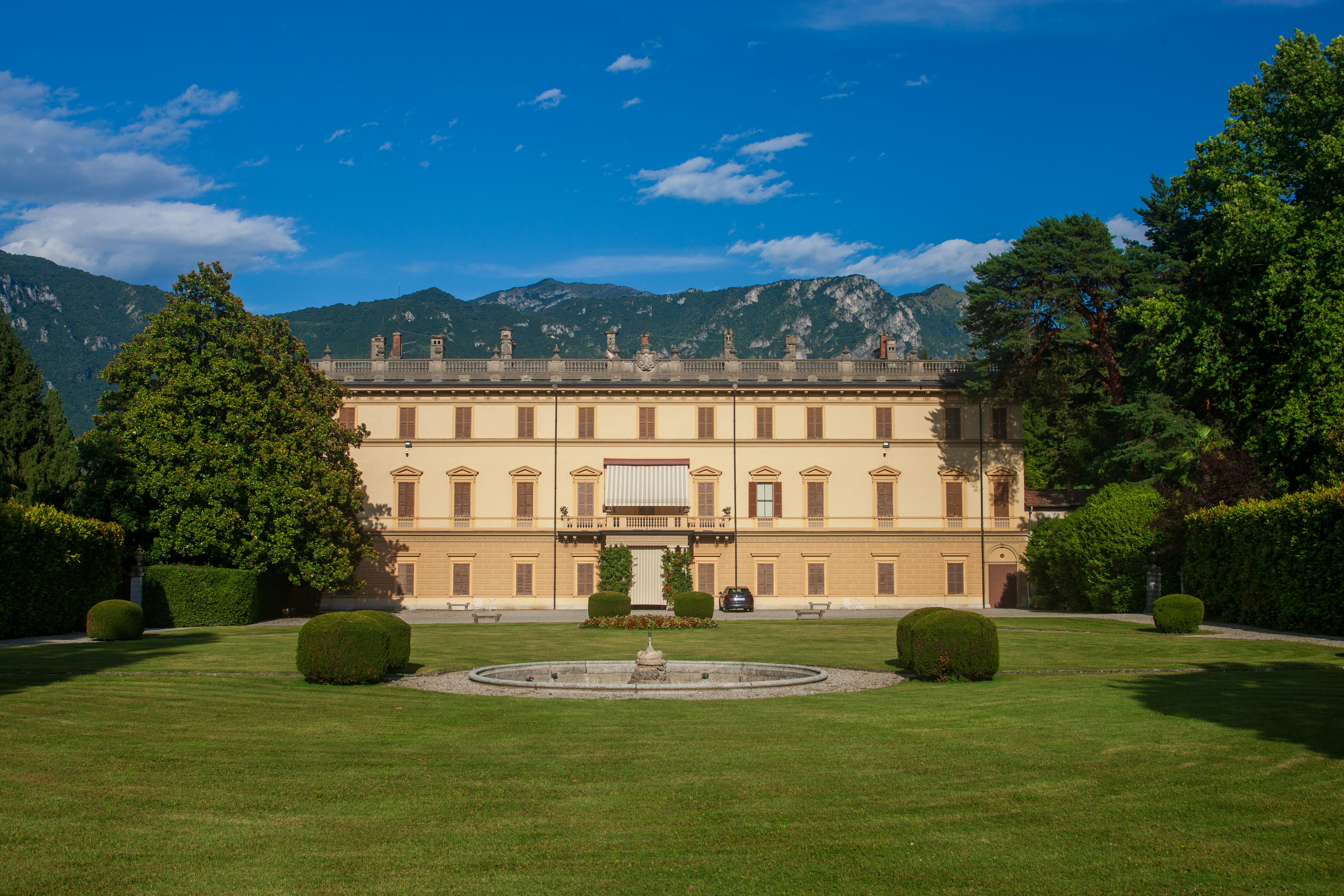 Symmetrical villa garden with central fountain under Alpine backdrop