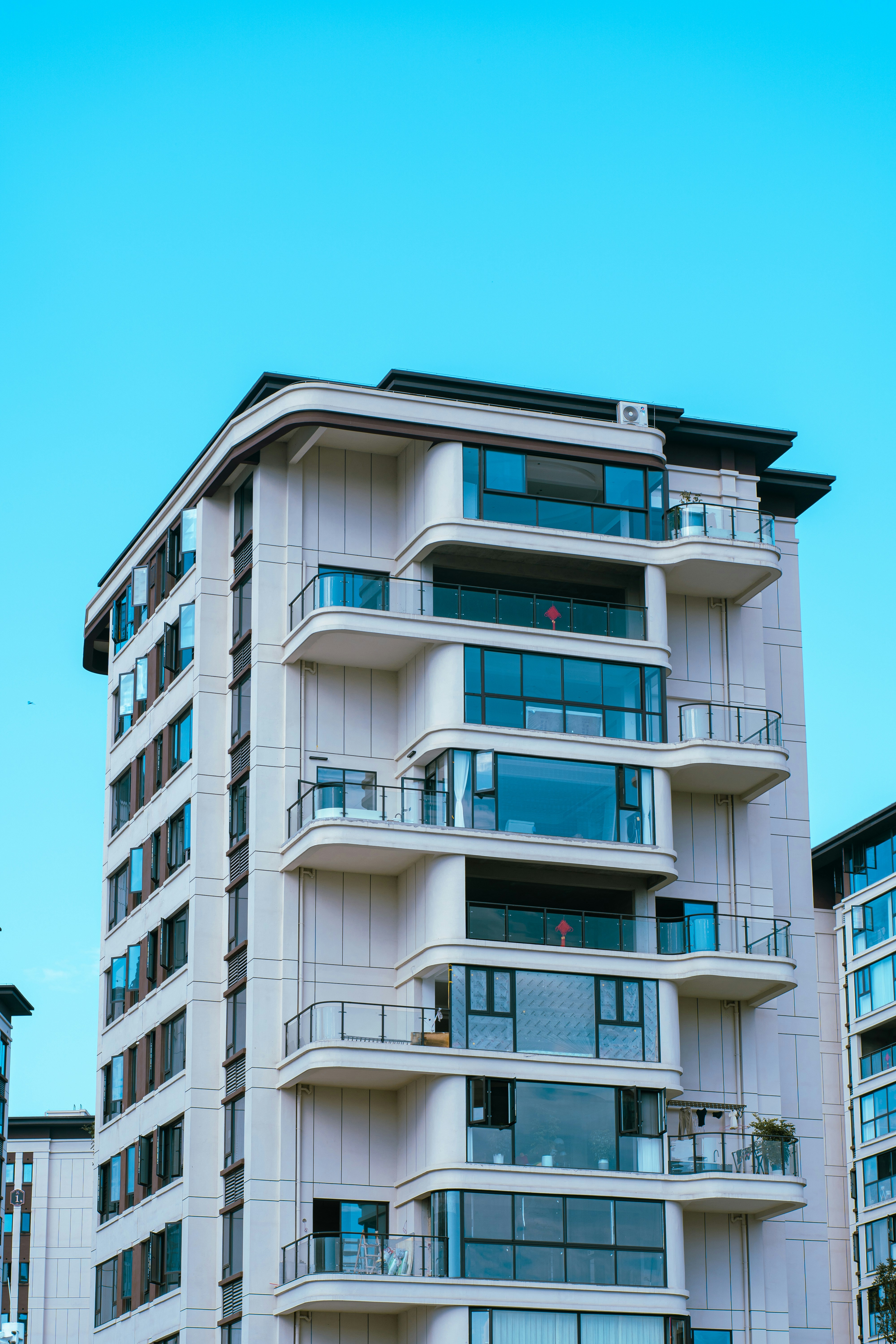 Vertical Habitat: Modern Balconies Ascend into a Sky-Blue Afternoon