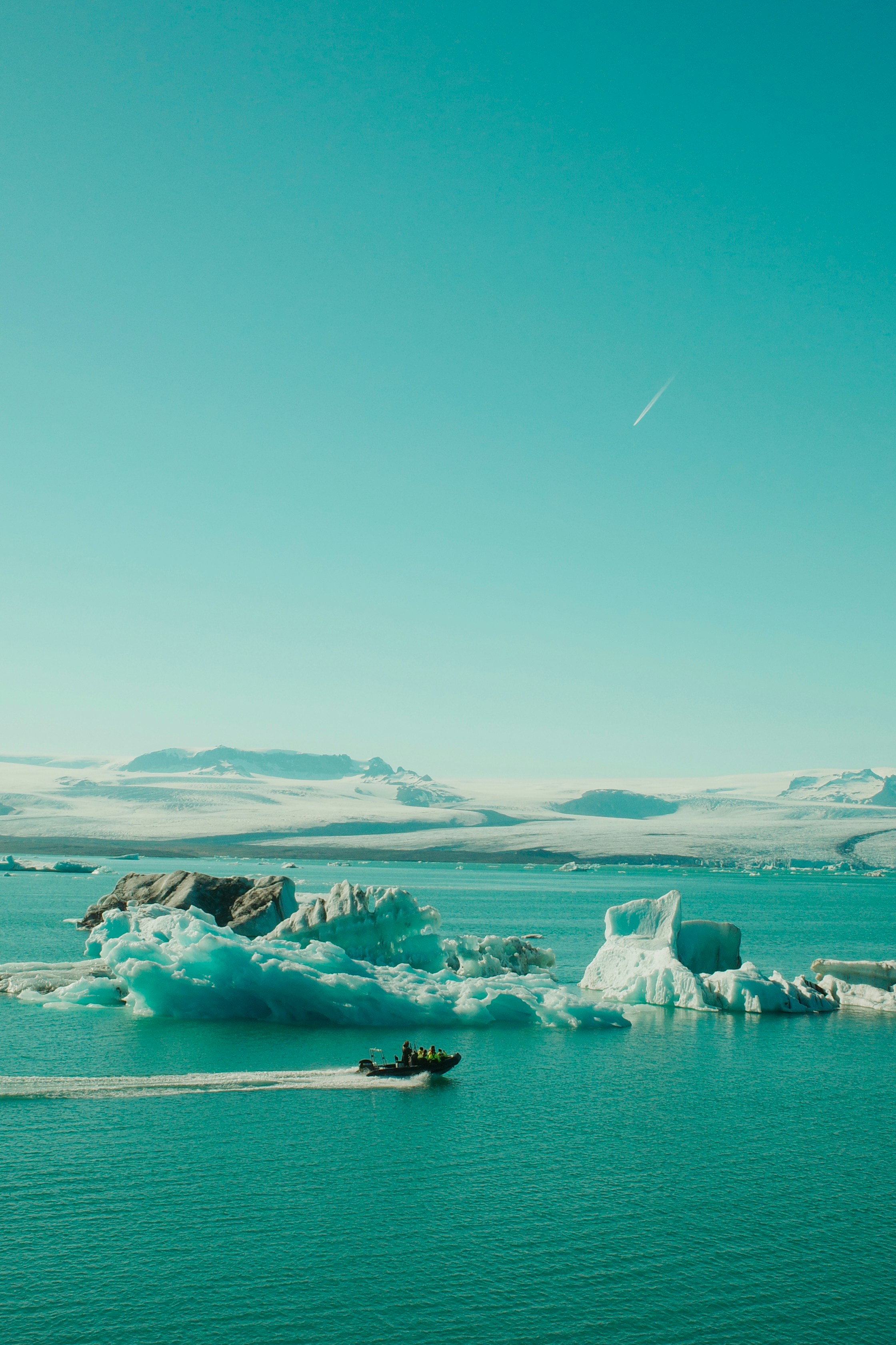 Icebound Silhouette: A Narrow Boat Traverses Teal Fjord