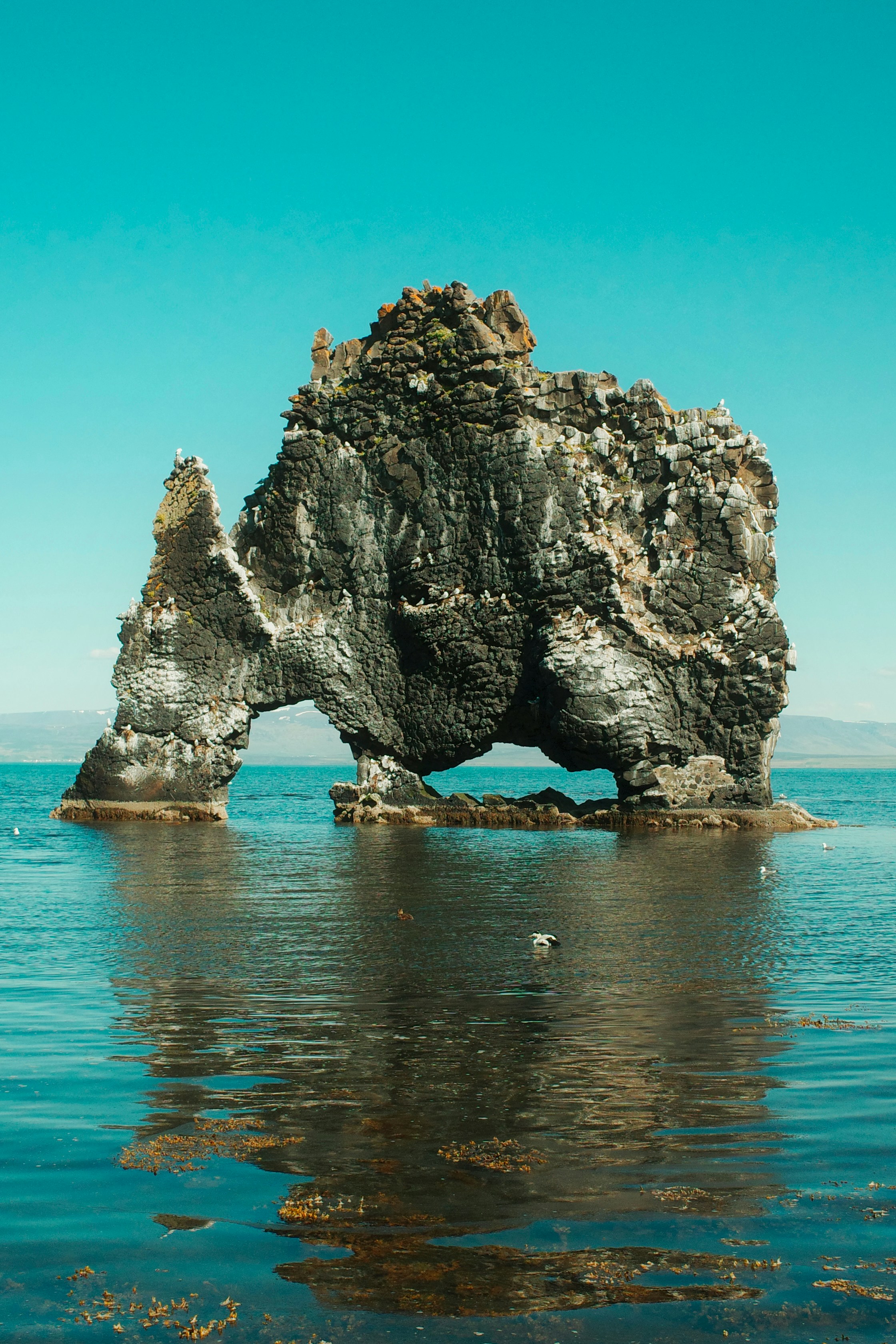 Stone Arch in Calm Seas: An Isolated Sea Rock Ringed by Blue