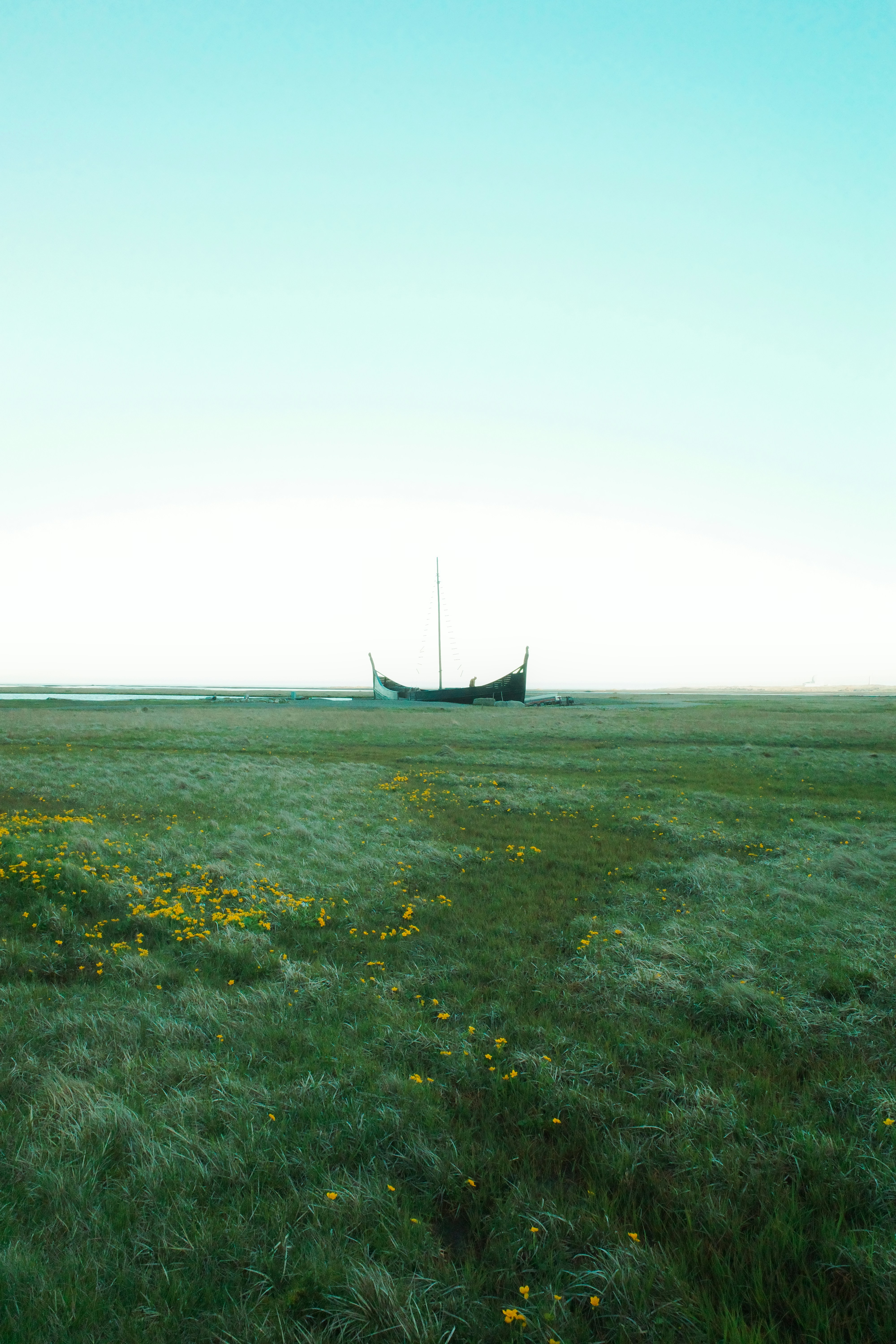 A solitary boat on a quiet estuary under a cyan dawn sky