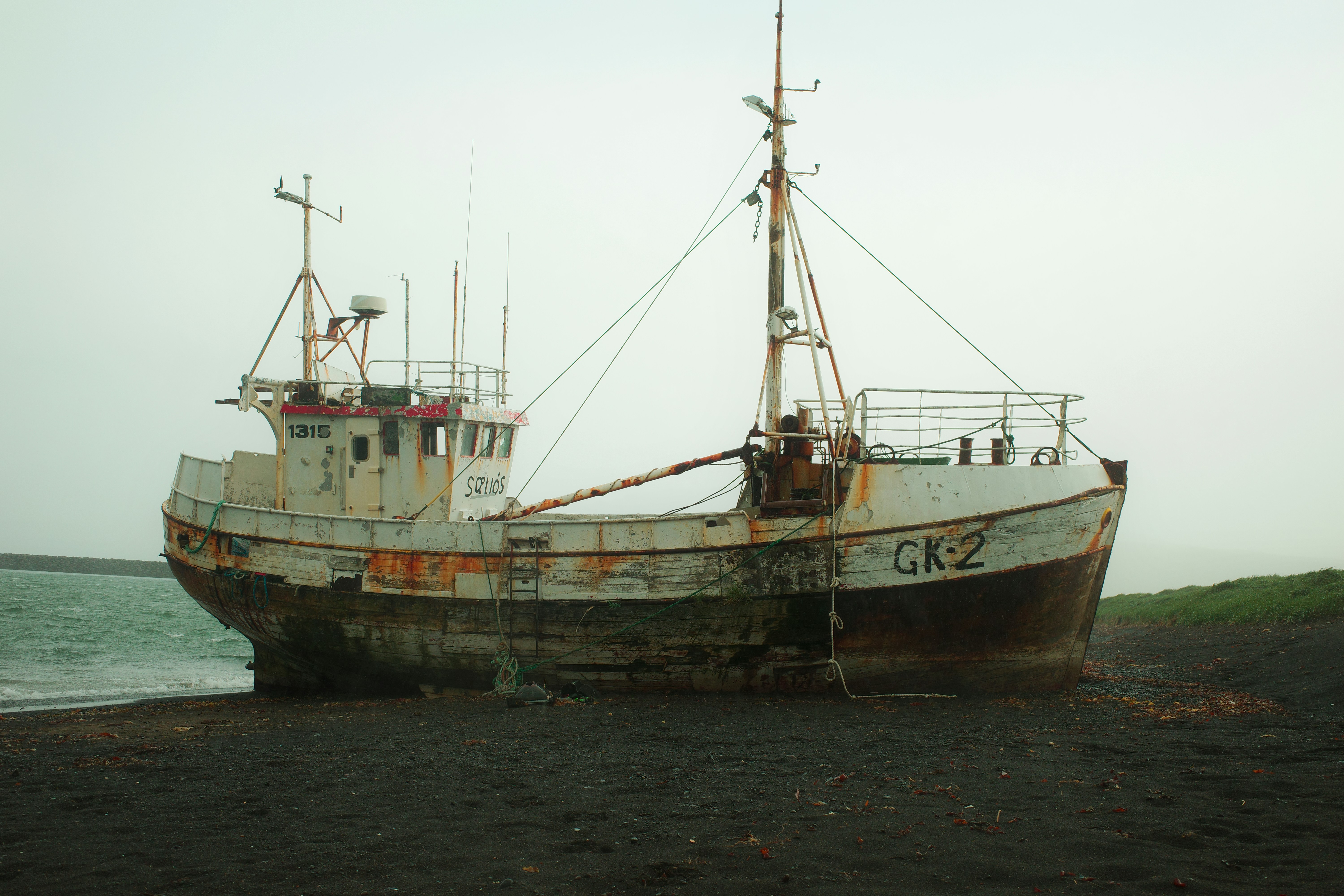 Rusting Halibut: A Beached Vessel’s Quiet Tale on Charcoal Shore
