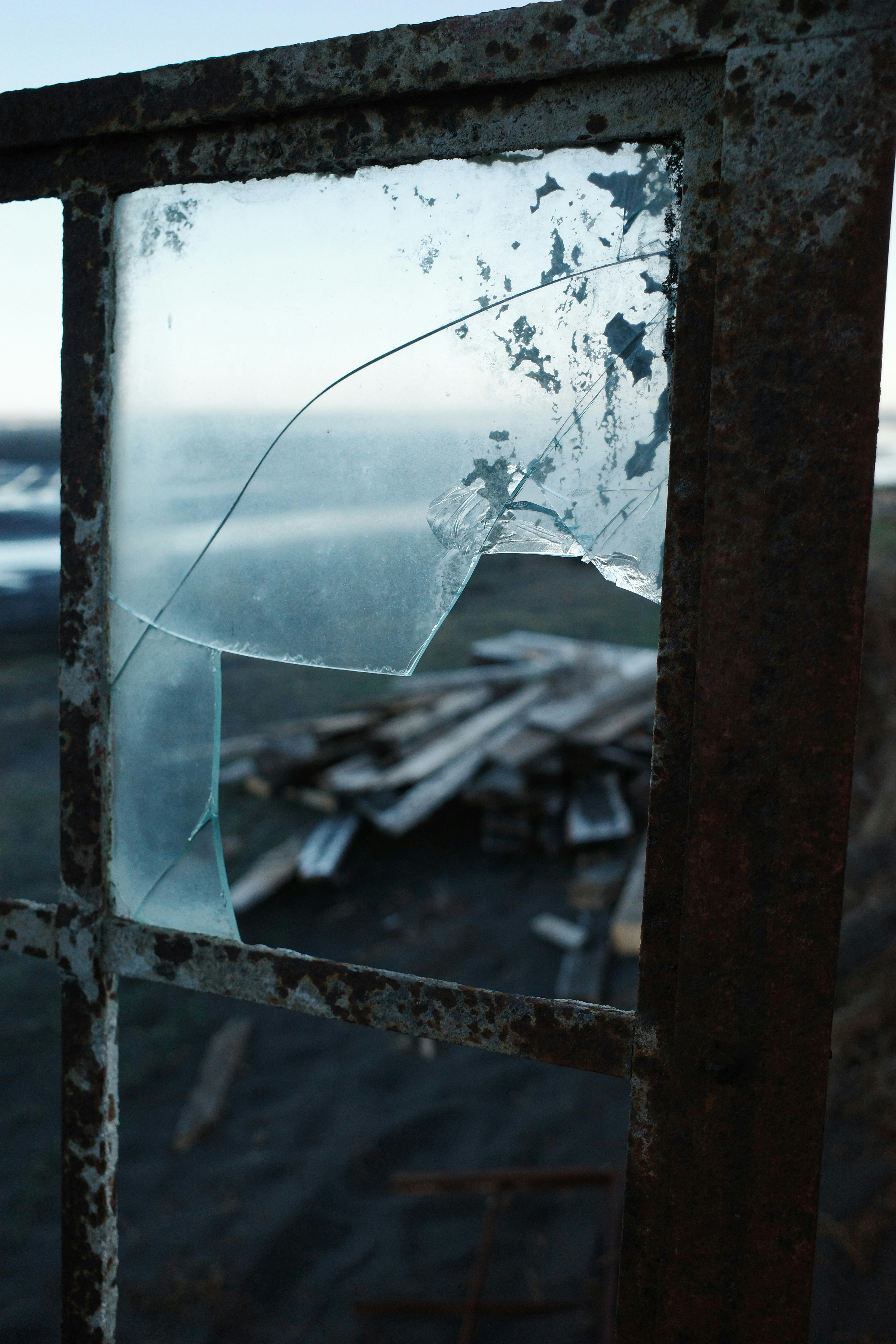 Broken Pane, Quiet Horizon: A Rusted Window to the Sea