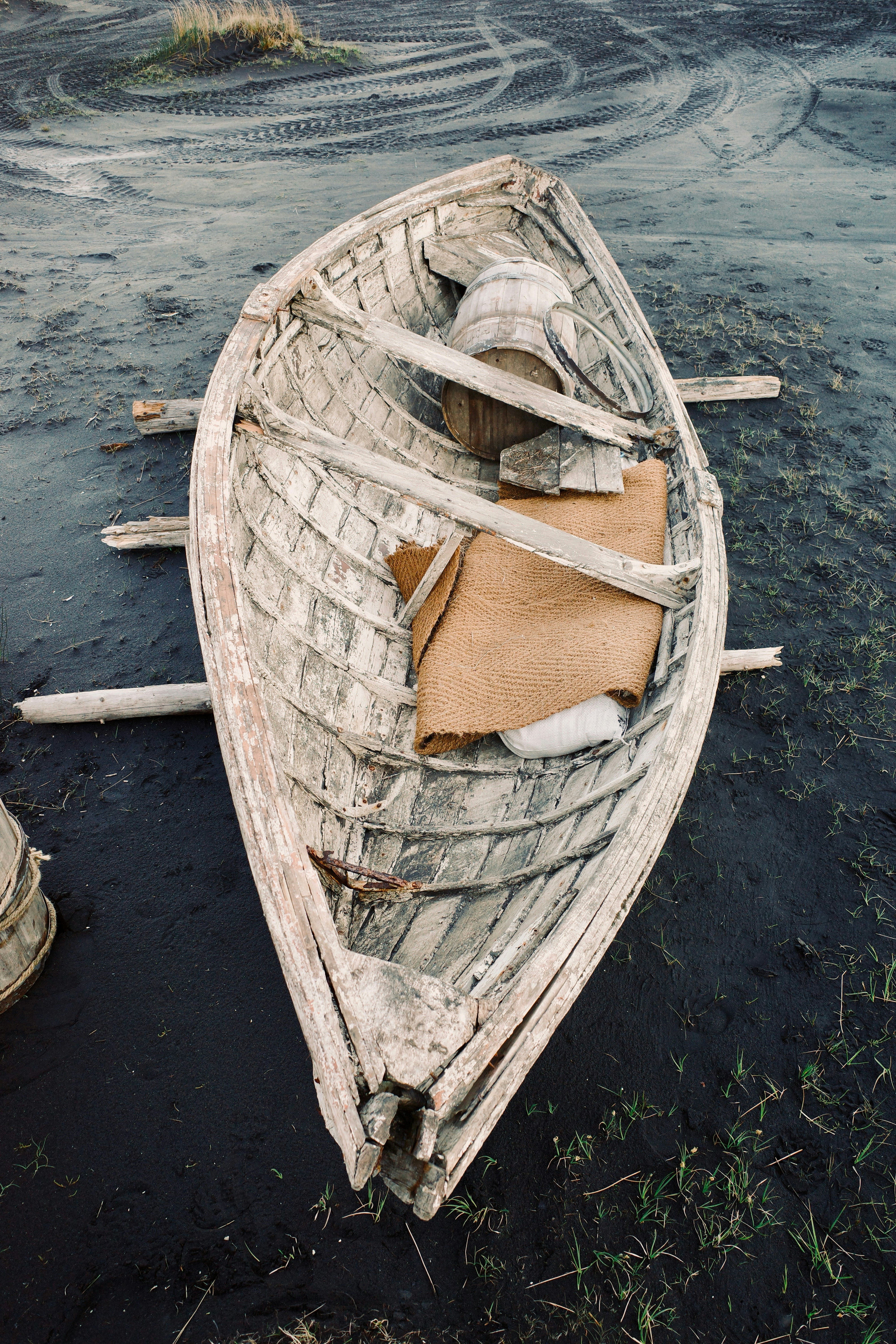 Weathered Rowboat Resting on Mudbank with Leaves and Watermark Circles