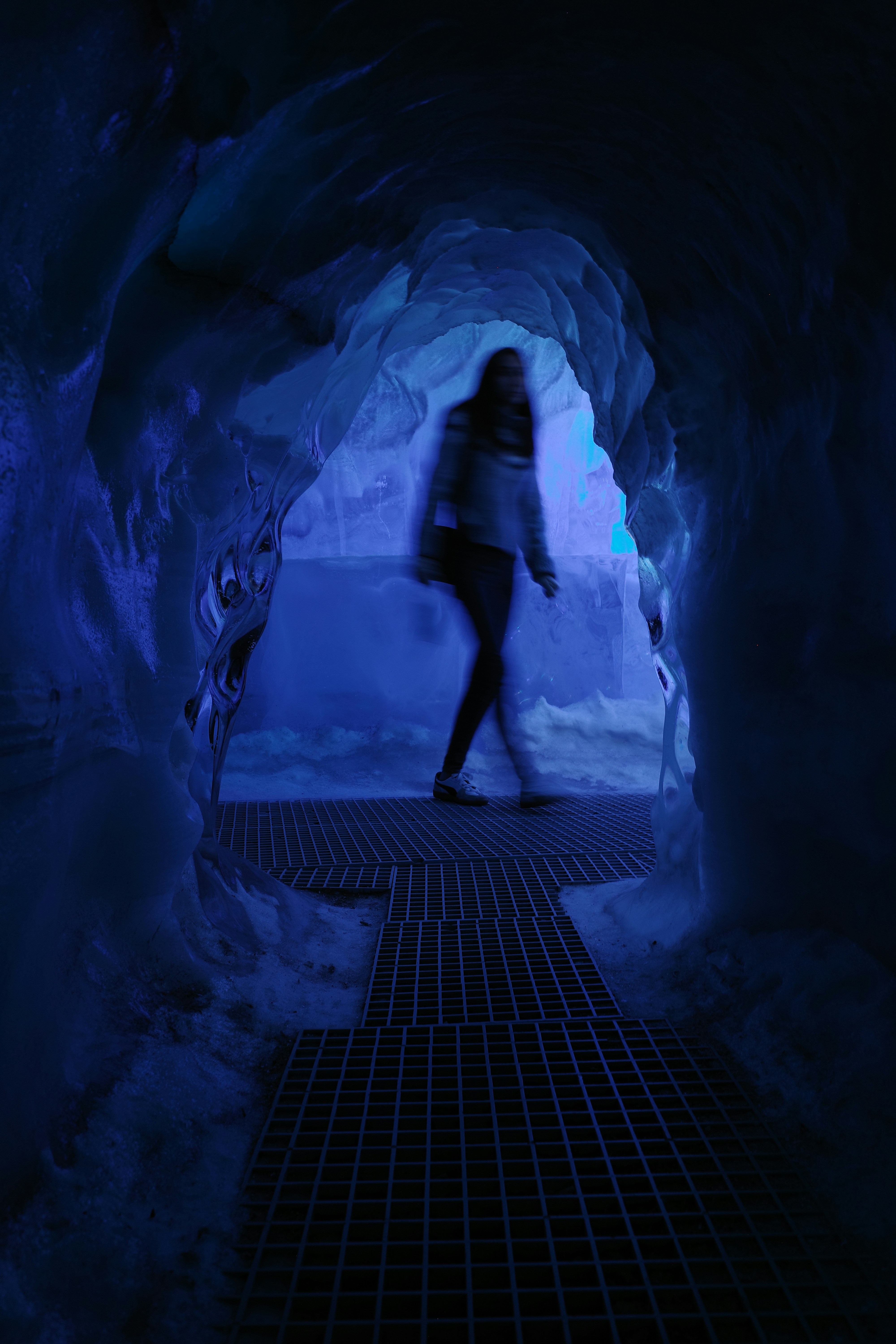 Blue Ice Tunnel: A Quiet Figure Steps Through the Frozen Arch