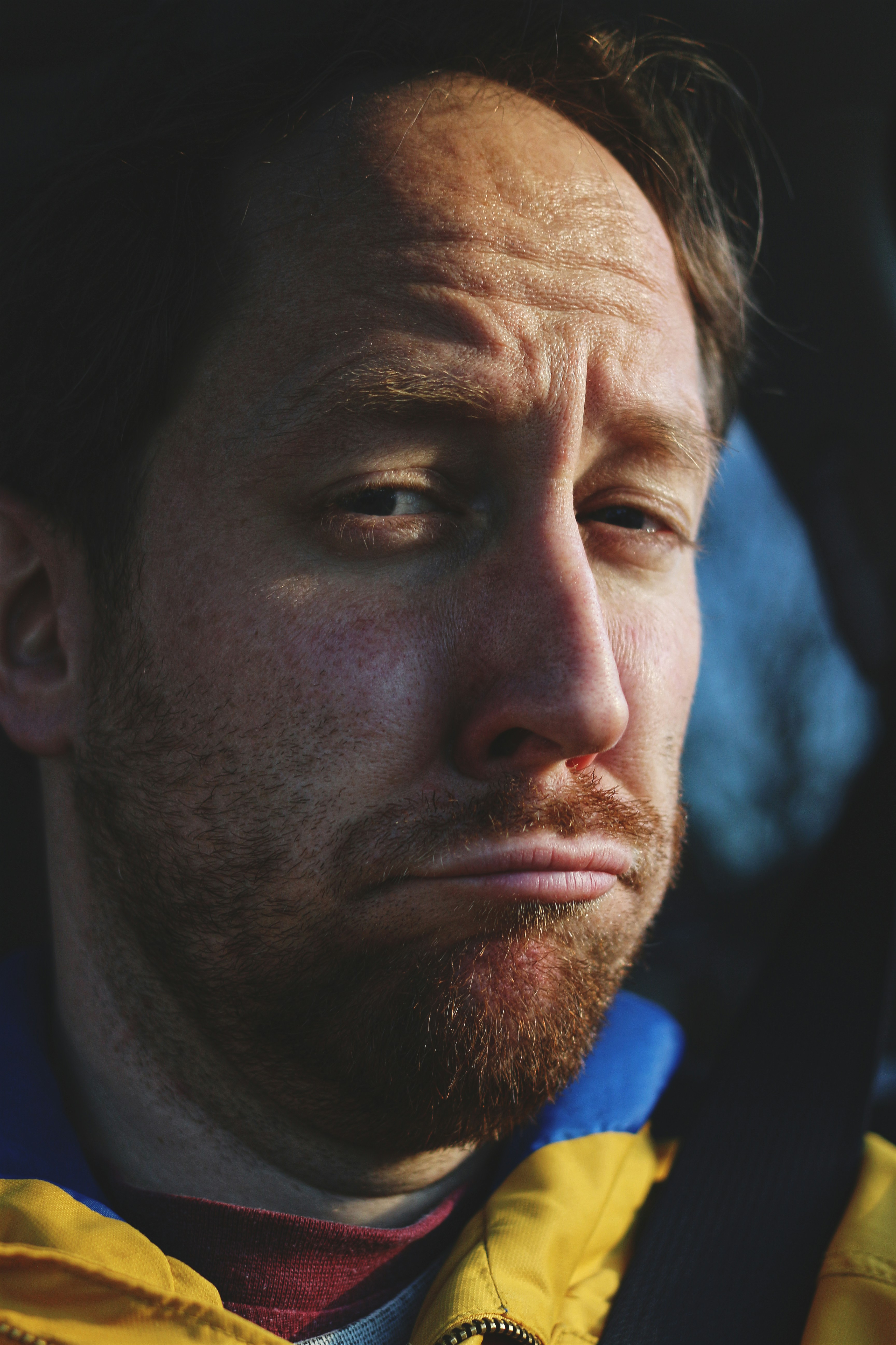 Close-up of a wary driver in a sunlit hood