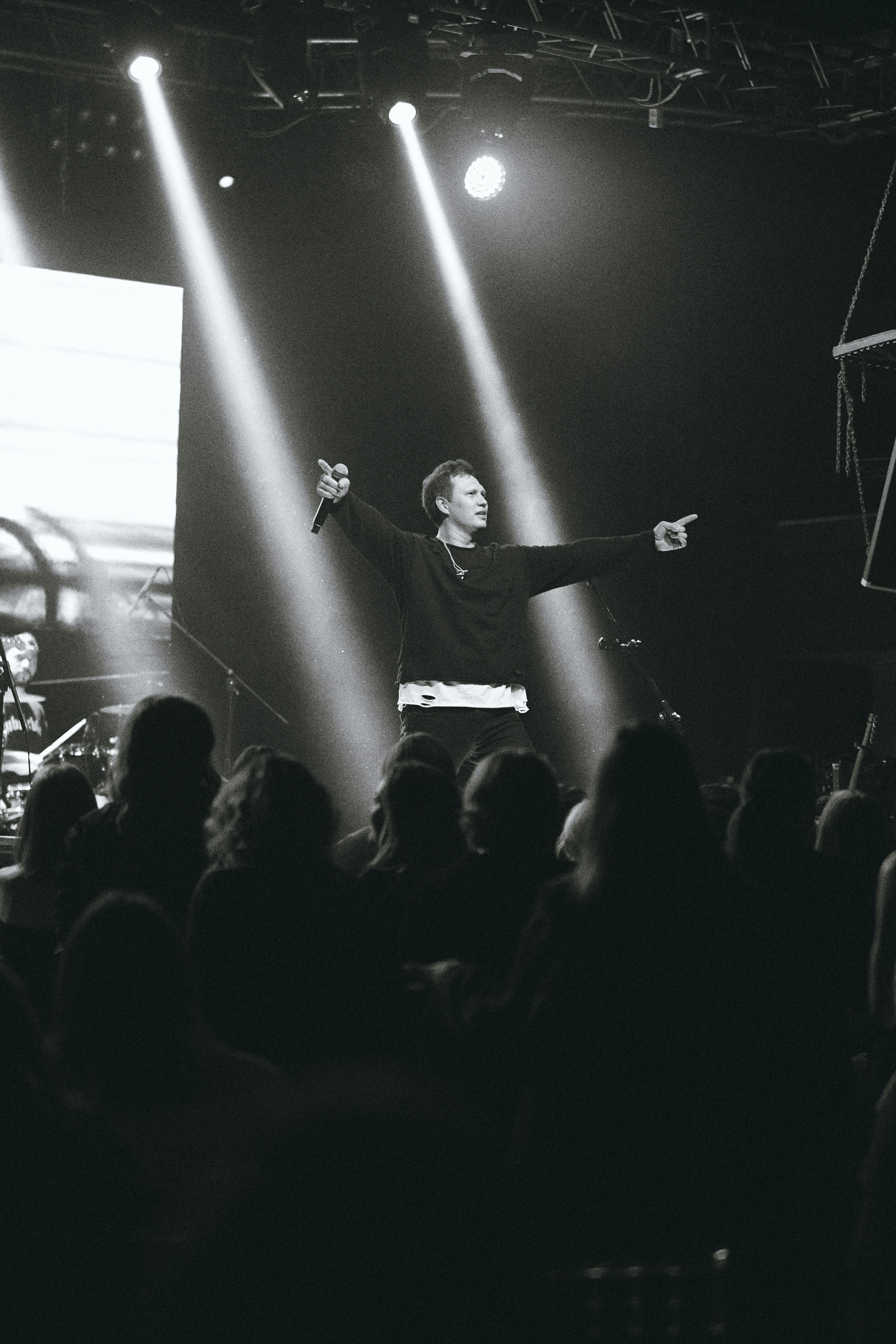 Center Stage: The Lead Singer Commands the Night with Outstretched Gaze