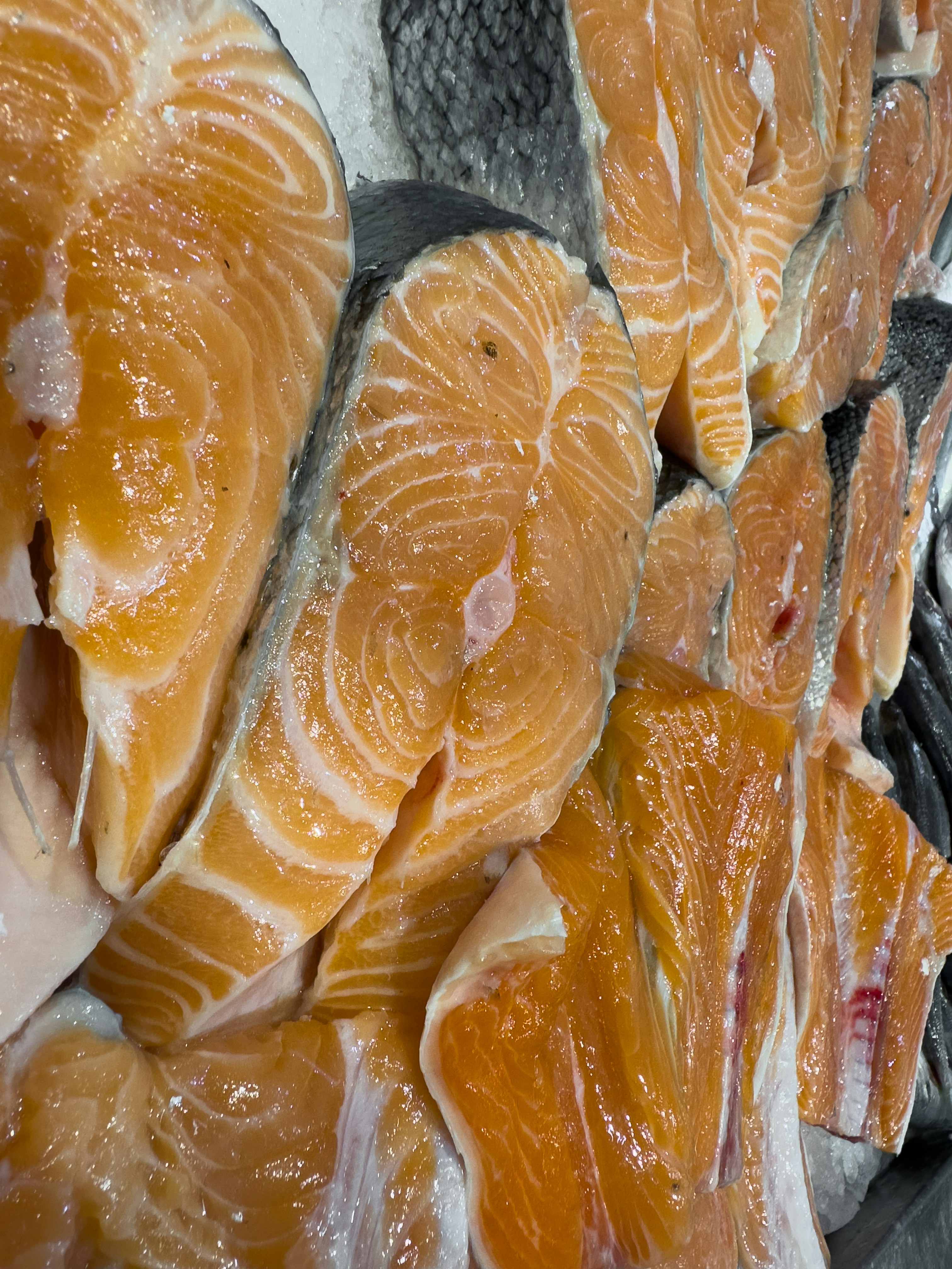 Sunlit Slices: Fresh Salmon Fillets Stacked in a Market Display