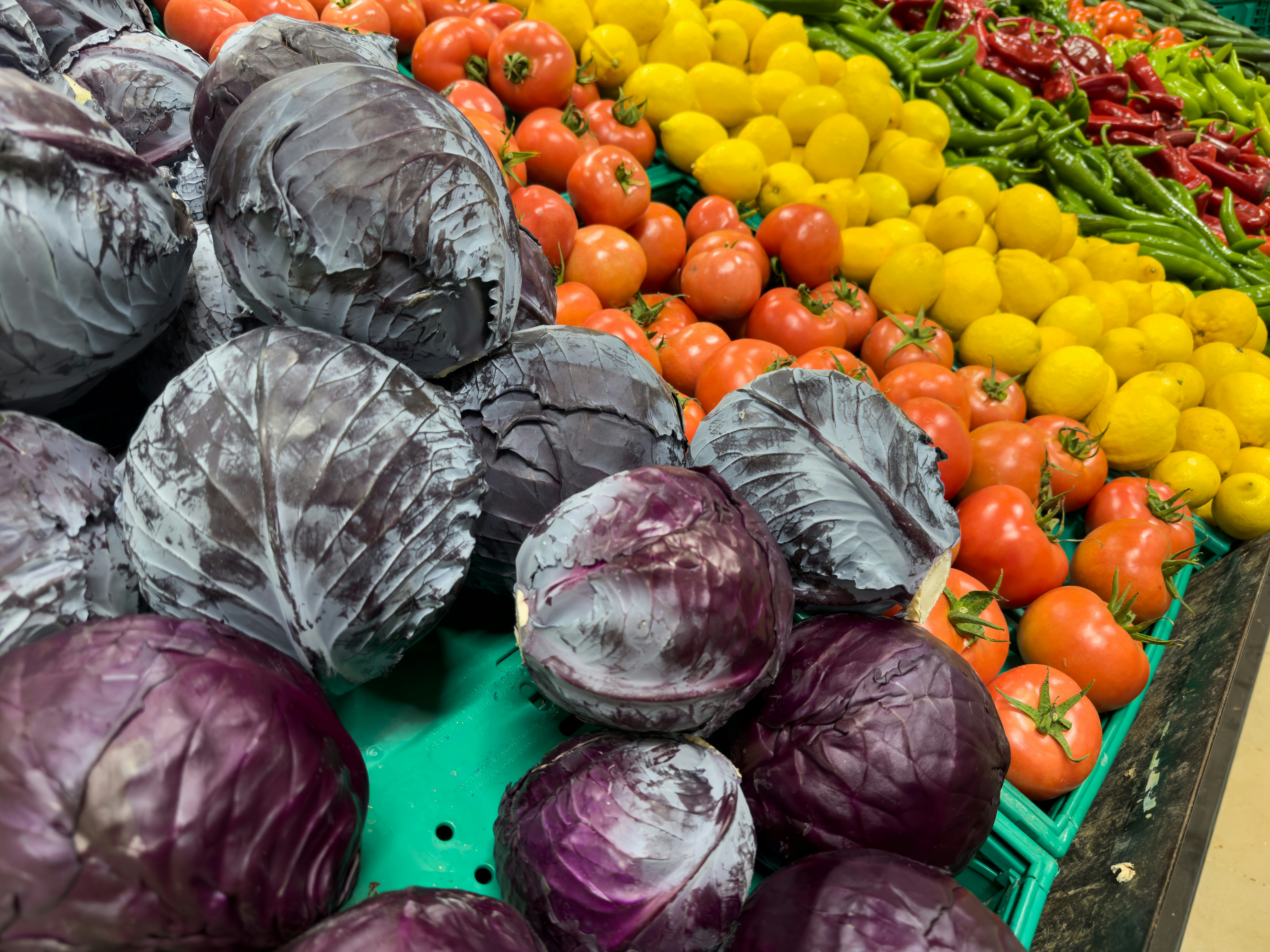Purple cabbages crowd the display beside a rainbow of cherry tomatoes