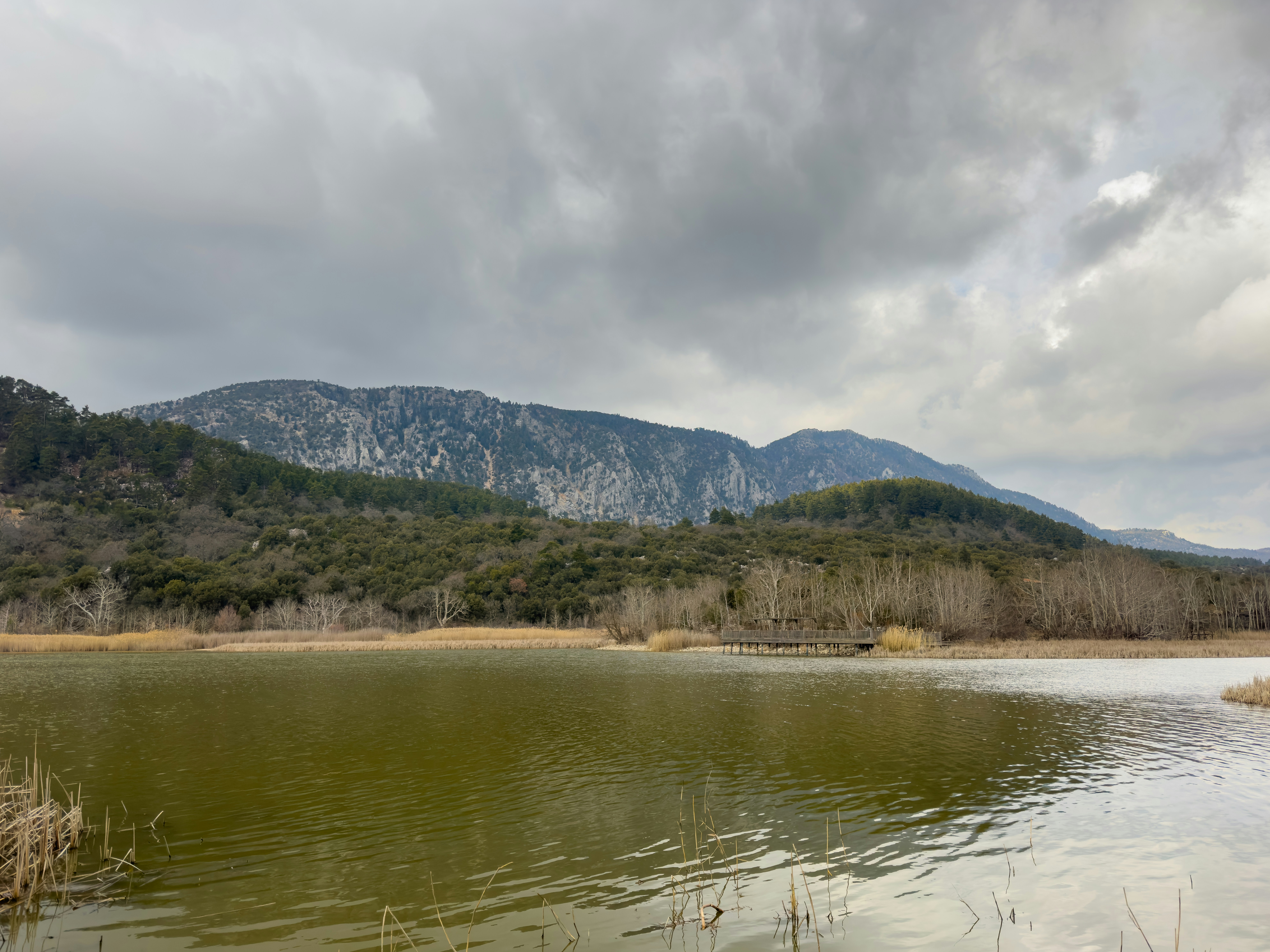 Quiet Lake Amid Distant Hills Beneath a Looming Sky