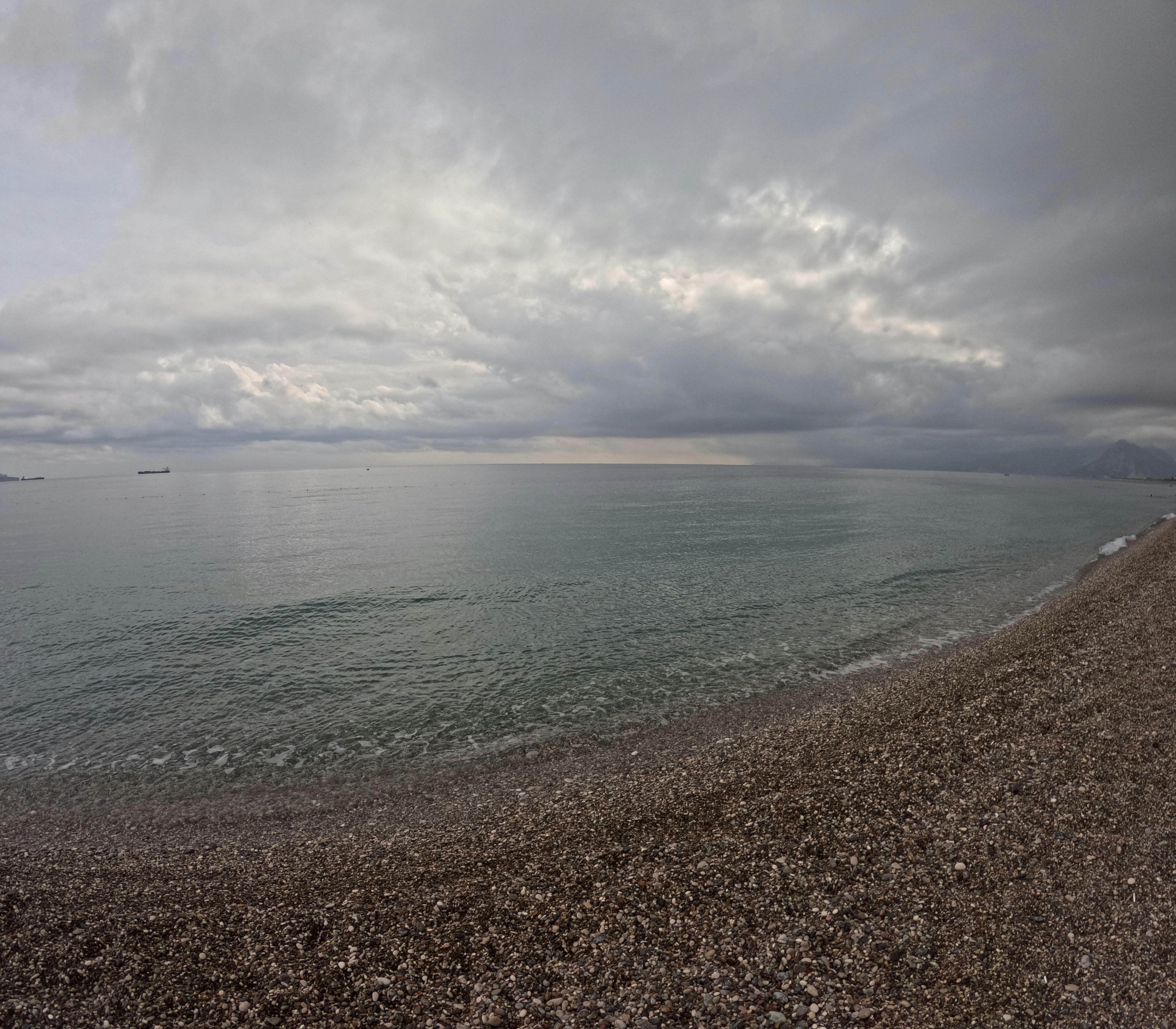 Overcast Shoreline: calm sea meeting a pebbled beach under a brooding sky