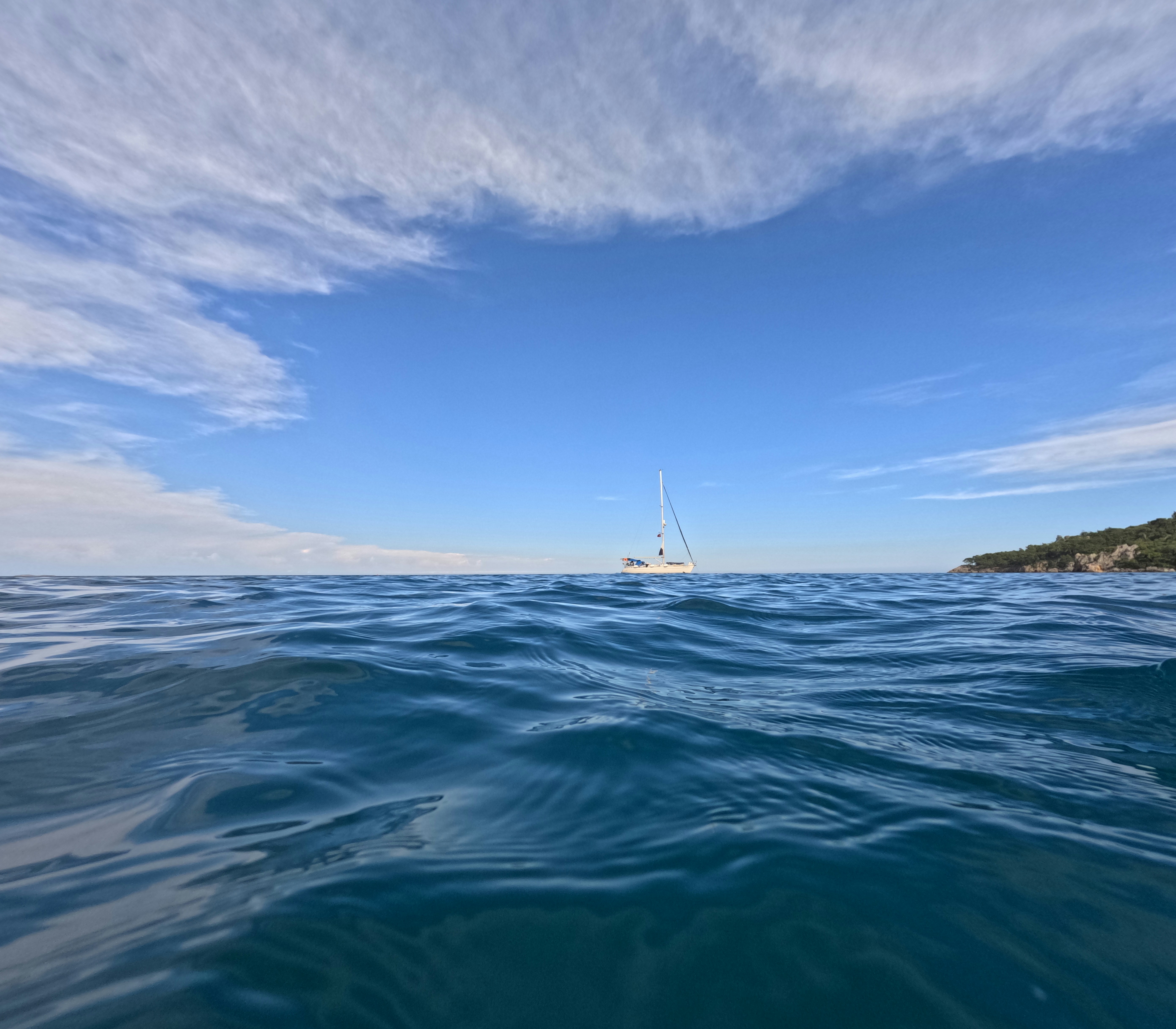 Calm Horizon: A Lone Sailboat Meets Atlantic Skies
