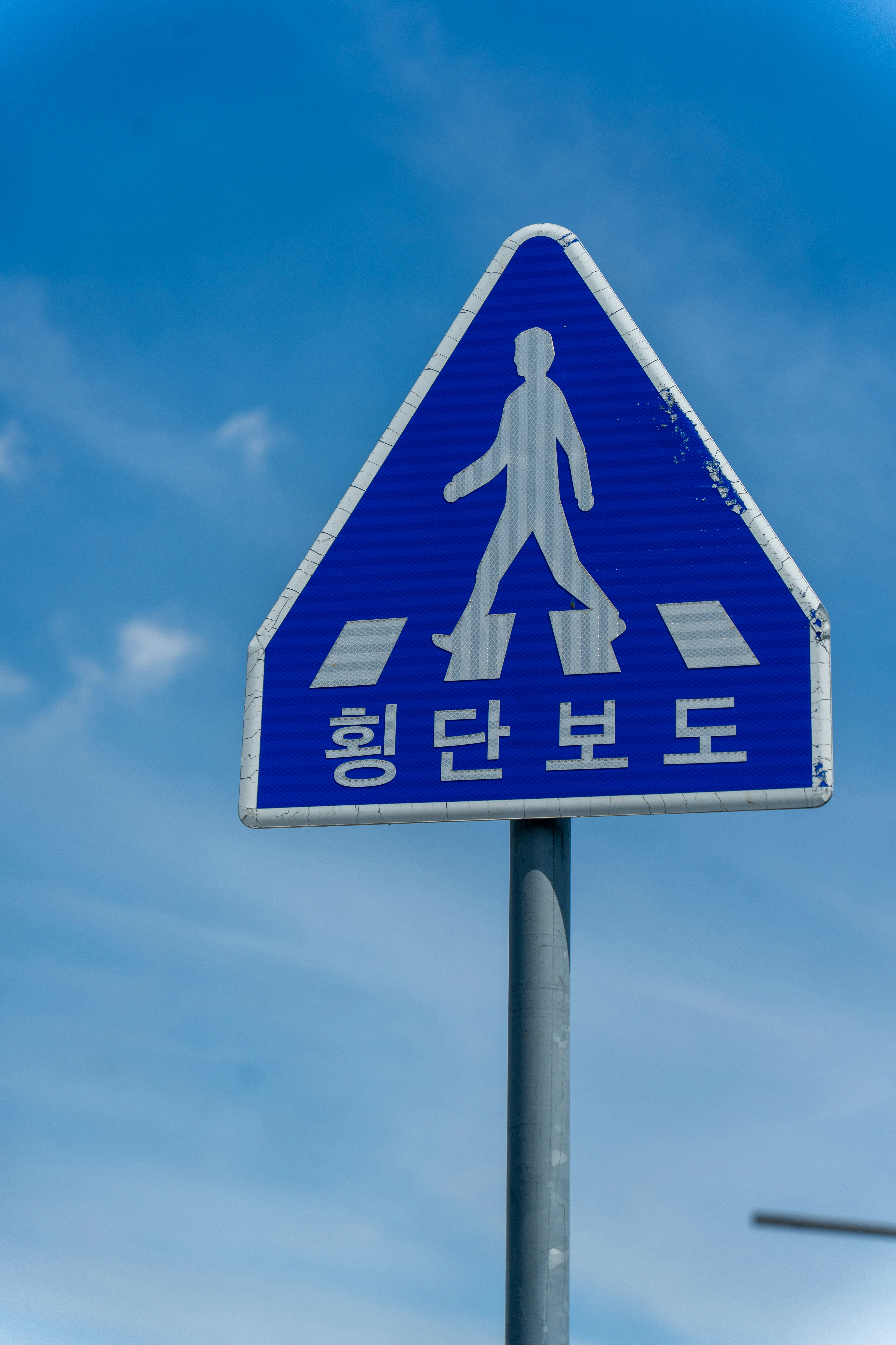Blue Pedestrian Crossing Sign Against a Clear Sky