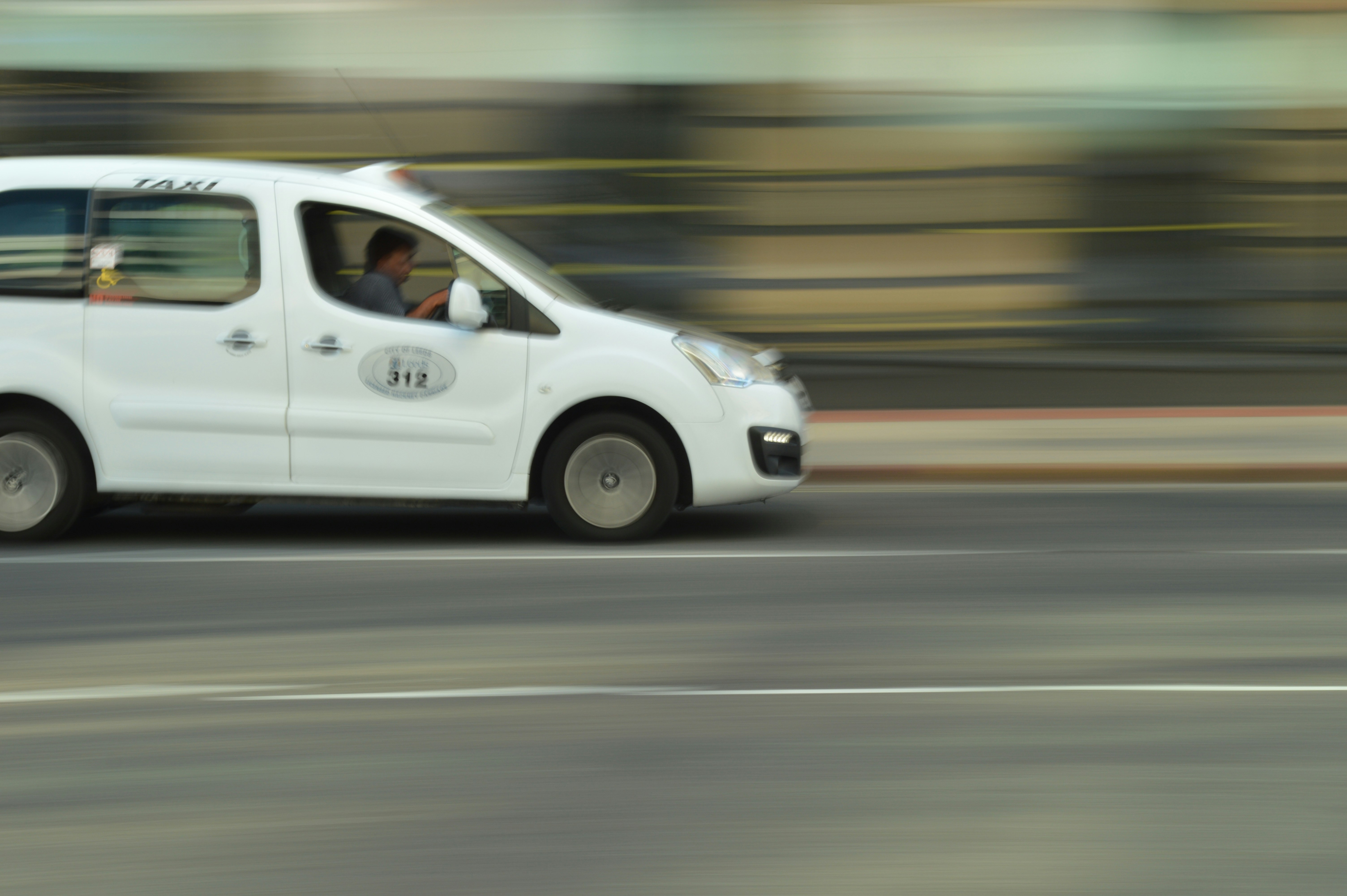 White taxi in motion blur across an urban street