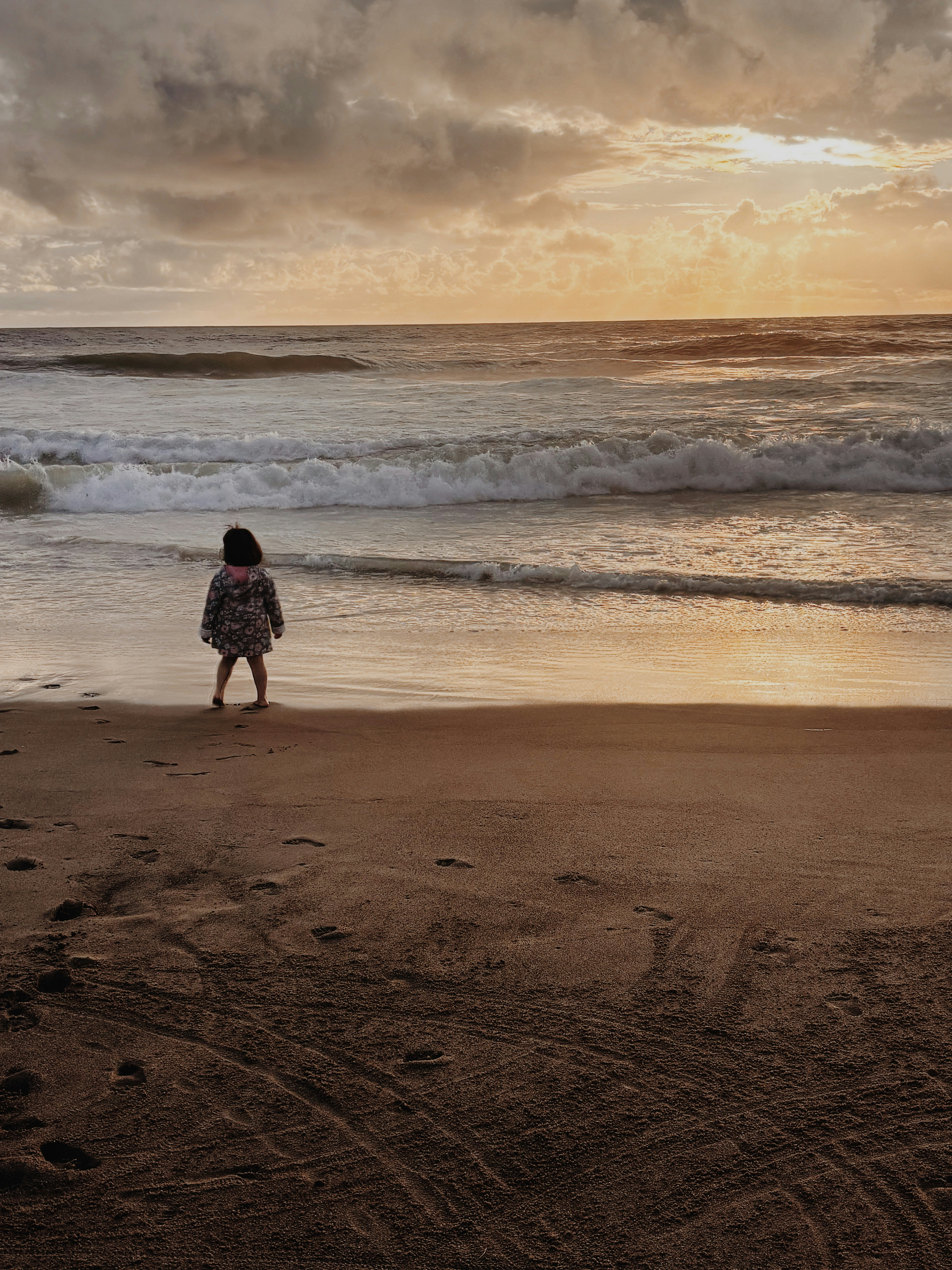 Child at the Edge: A Quiet Sunset Beach Moment