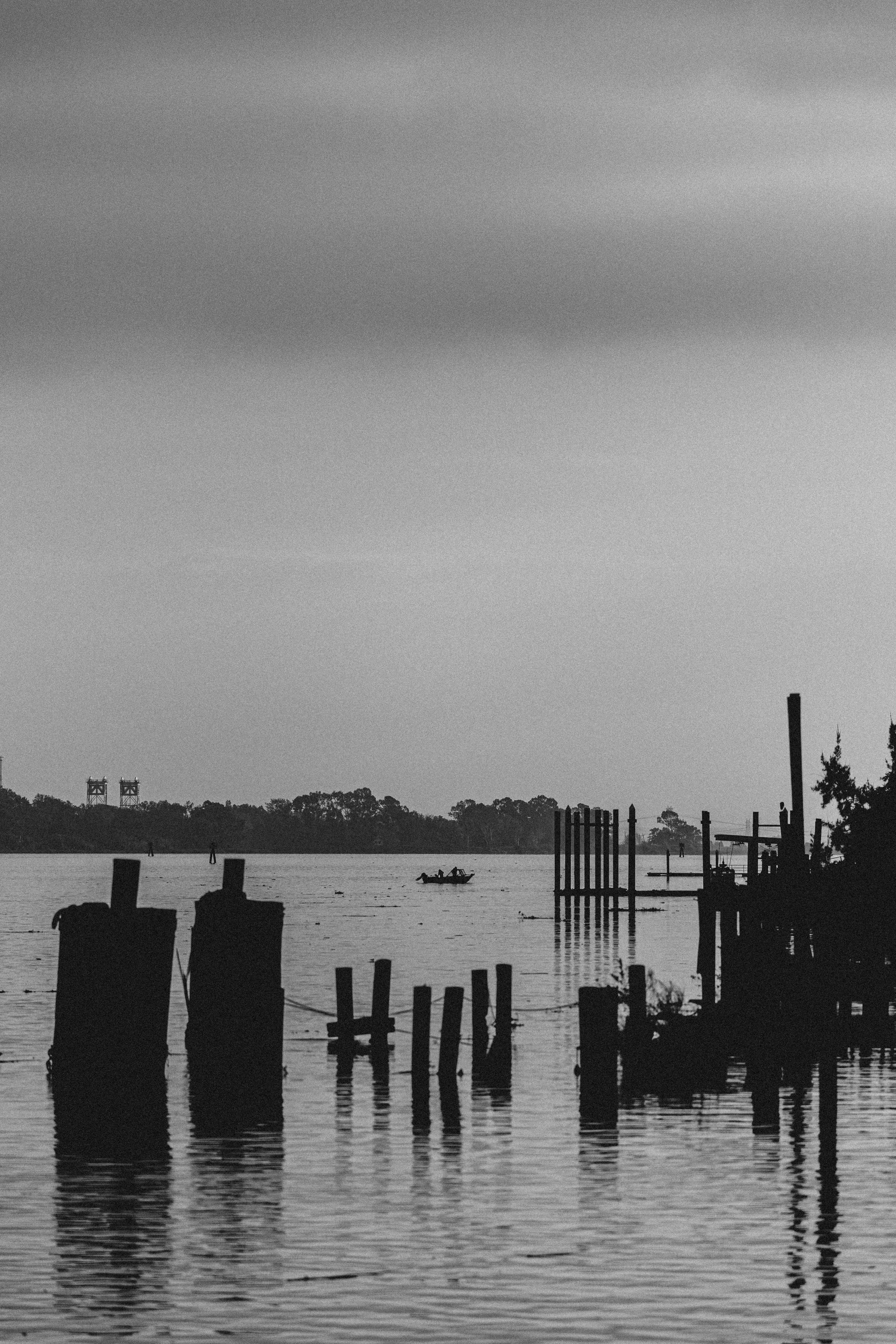 Distant Rowboat and Weathered Piers on a Quiet River
