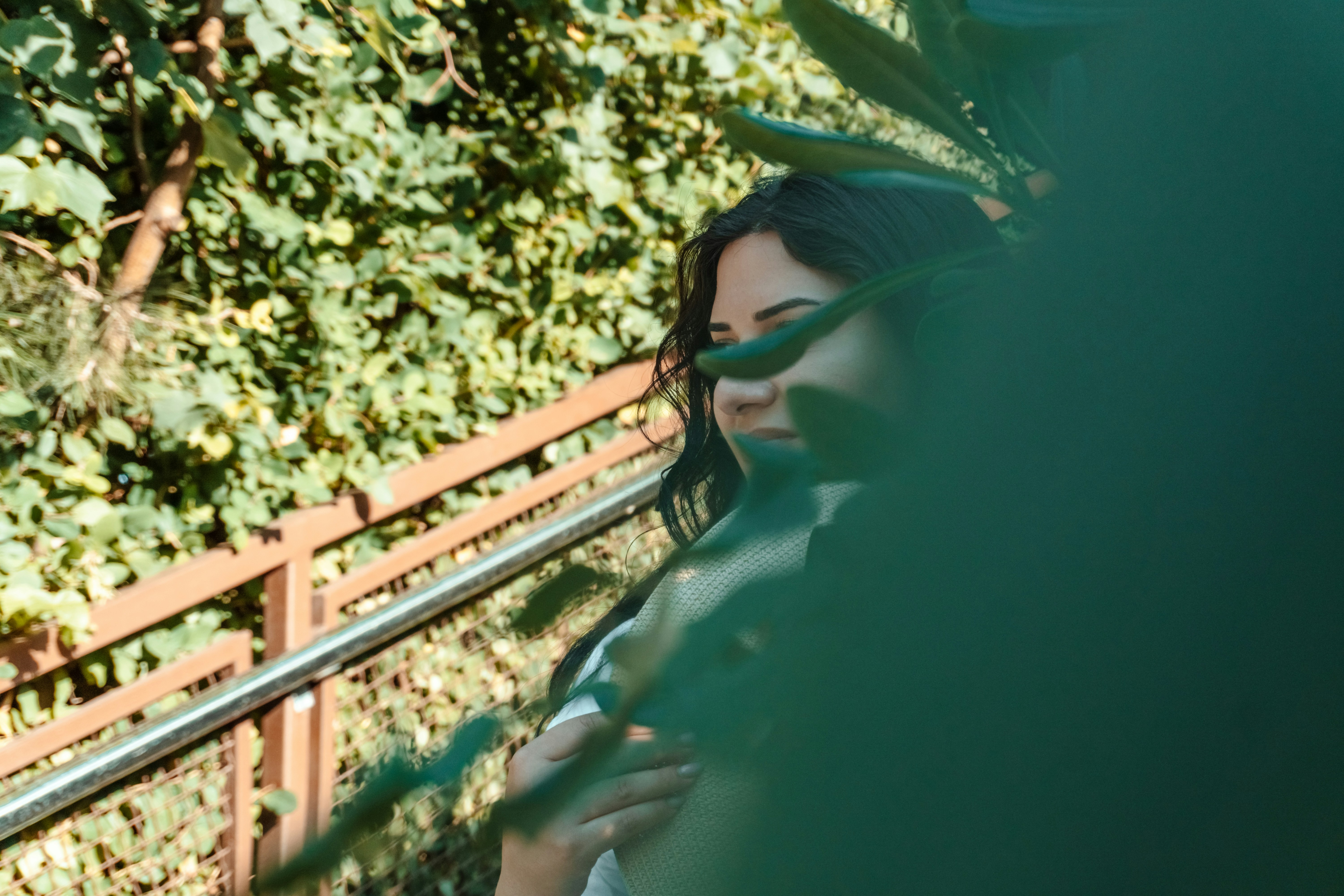 Hidden Portrait: A Subtle Gaze Behind Green Veils on a Riverside Path