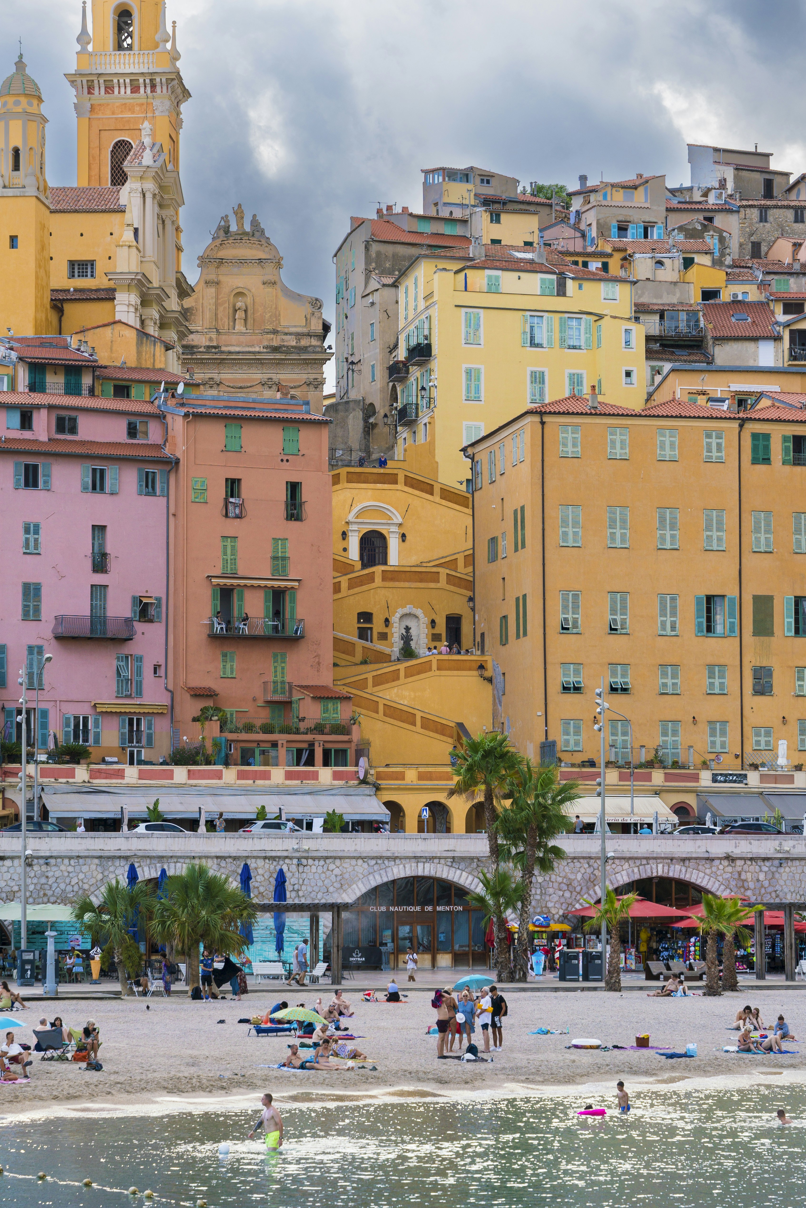 Colorful hillside village rises above a sunlit beach promenade