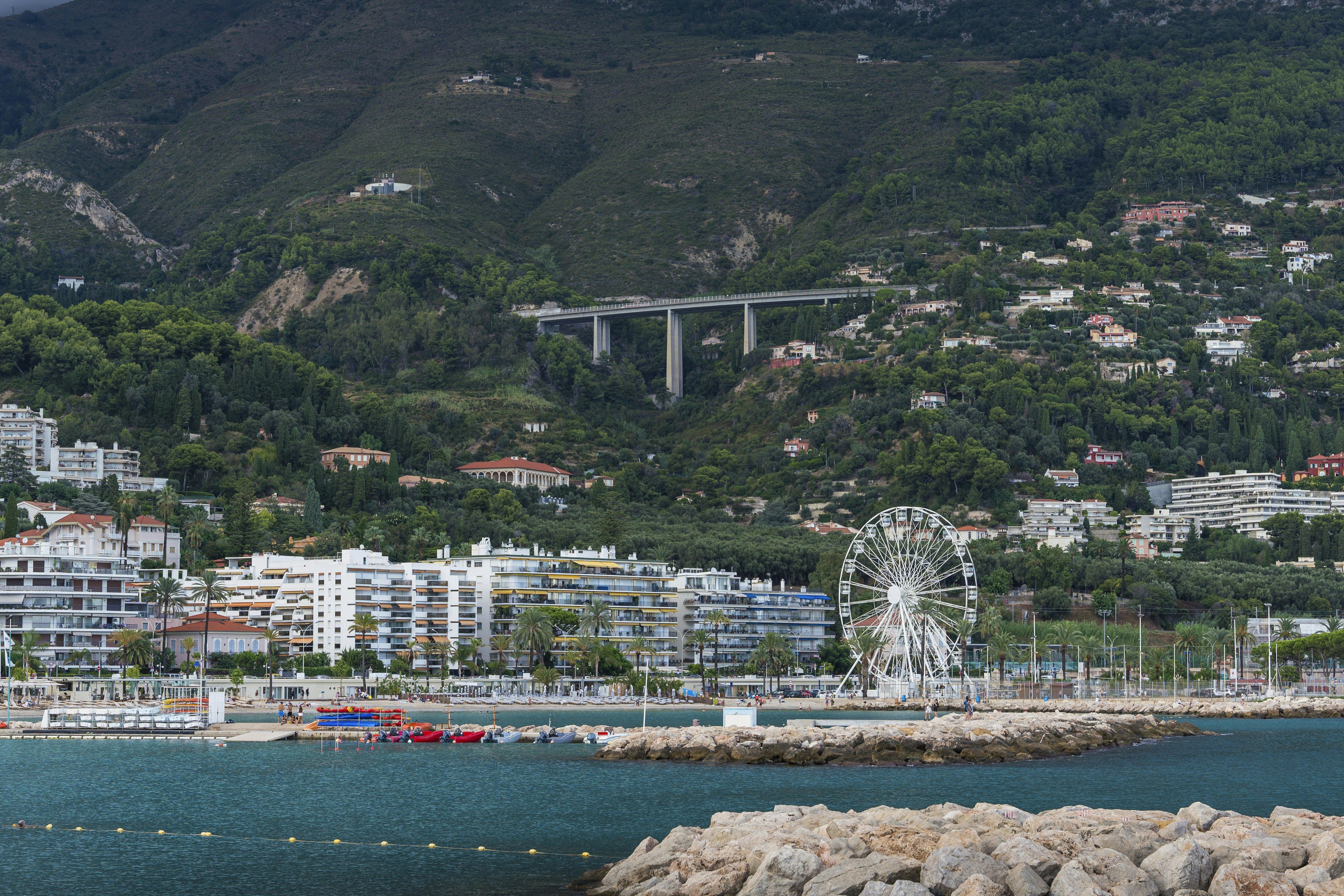 Coastal Town at Dusk: Ferris Wheel by the Sea and Mountain Backdrop