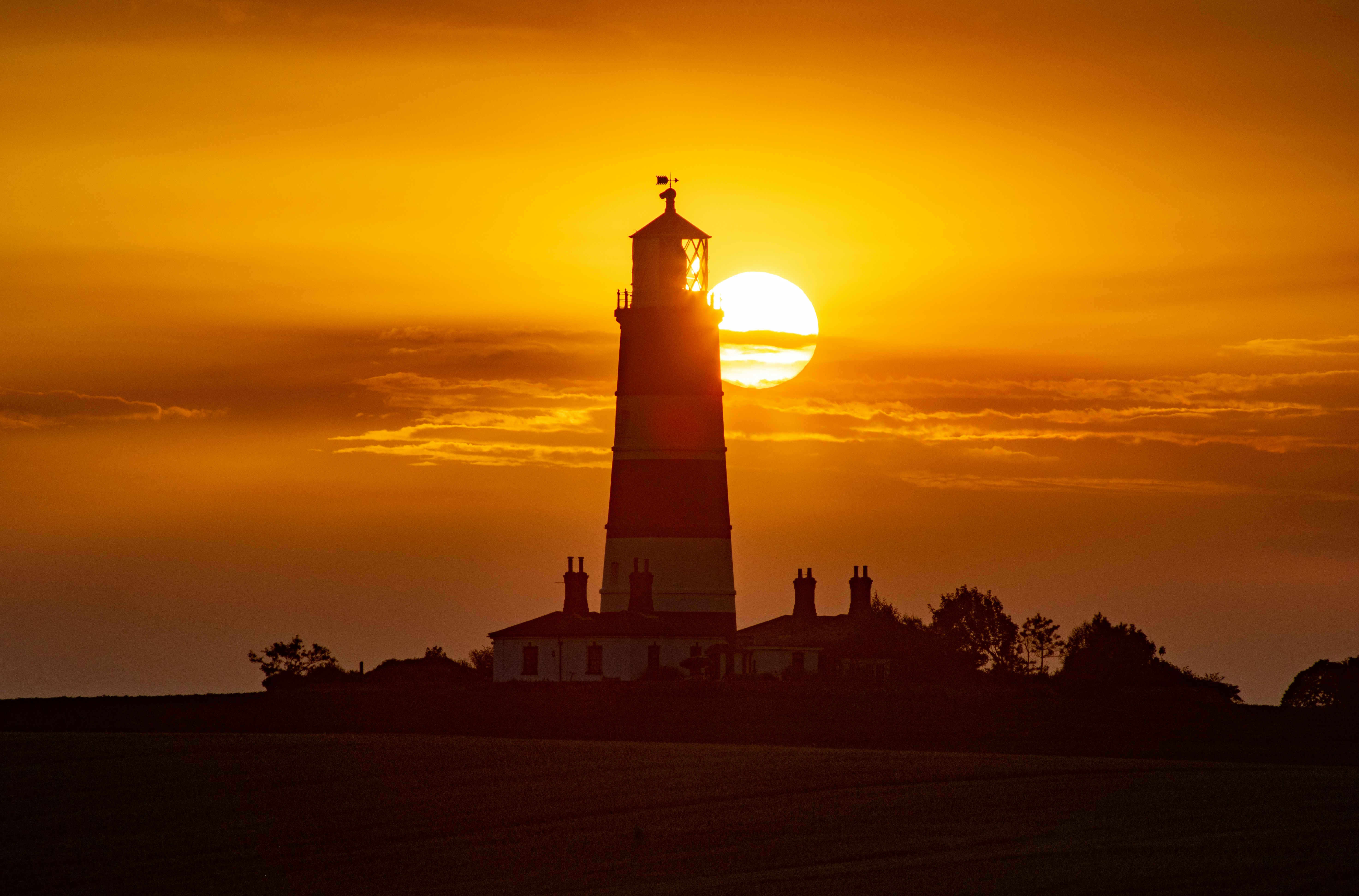Sunset Beacon: The Lighthouse Silhouette on Quiet Fields