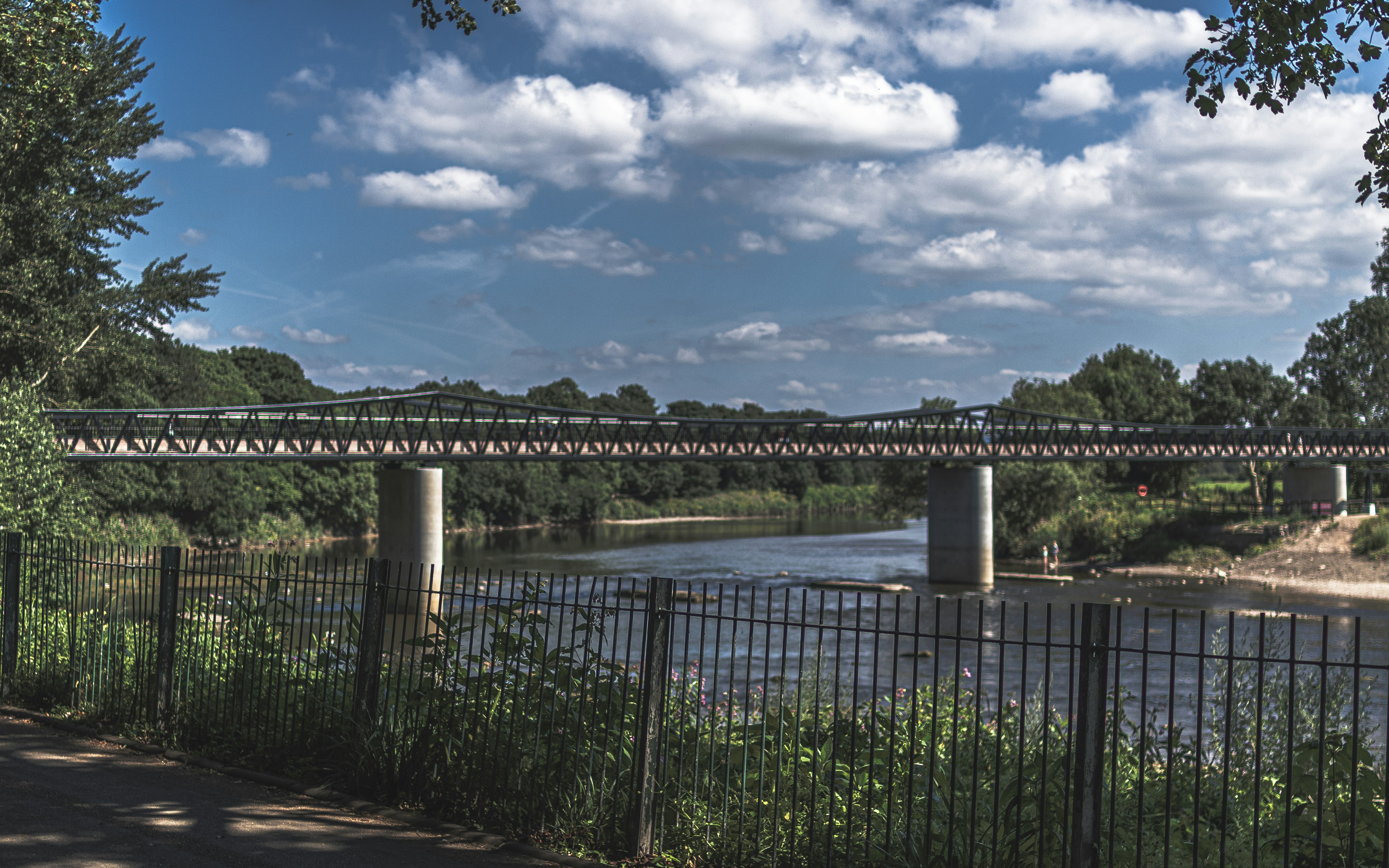 Bridge over Quiet River: A Sunlit Scene Framed by Foliage