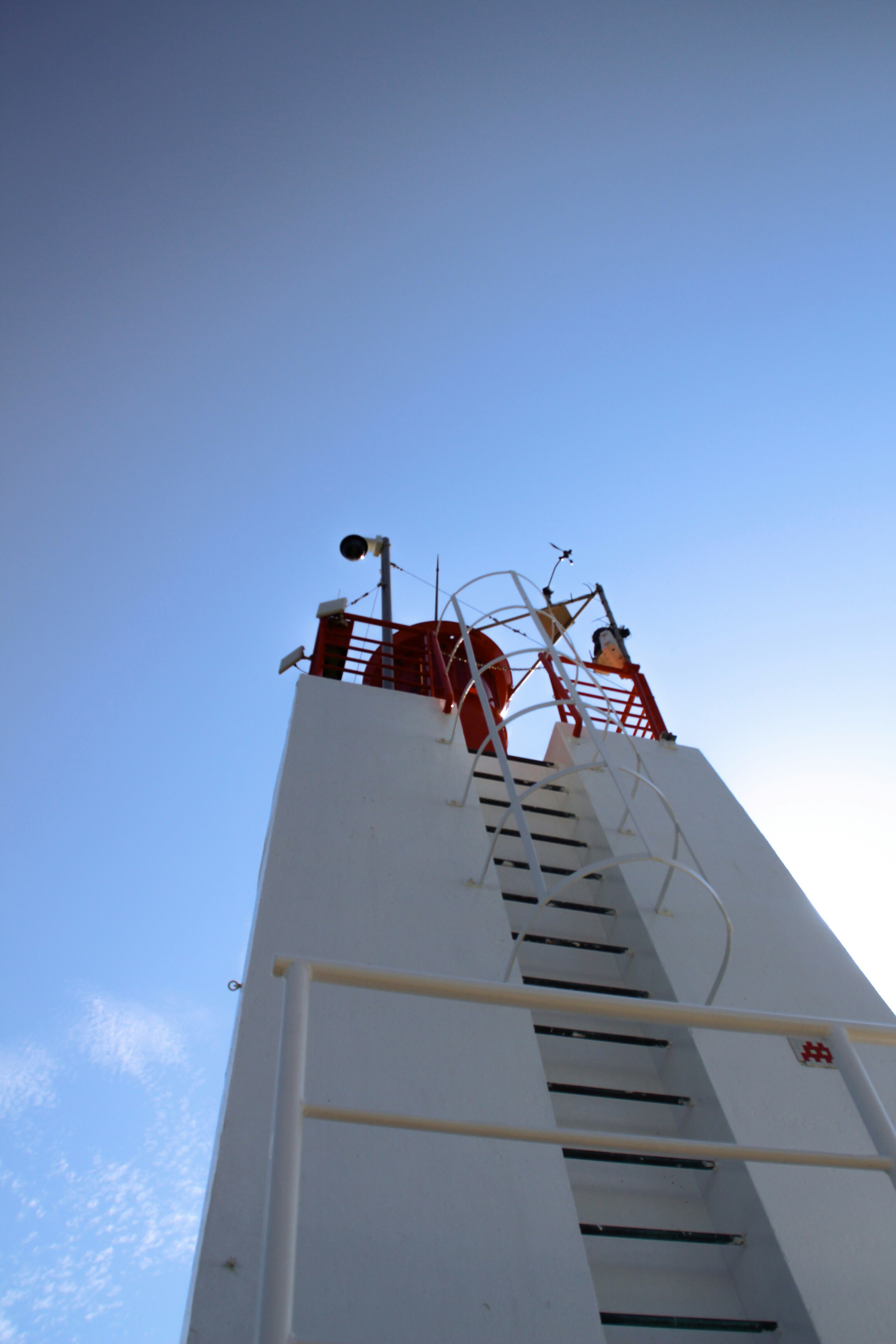 Lighthouse Ascent: White Tower Against a Clear Blue Sky