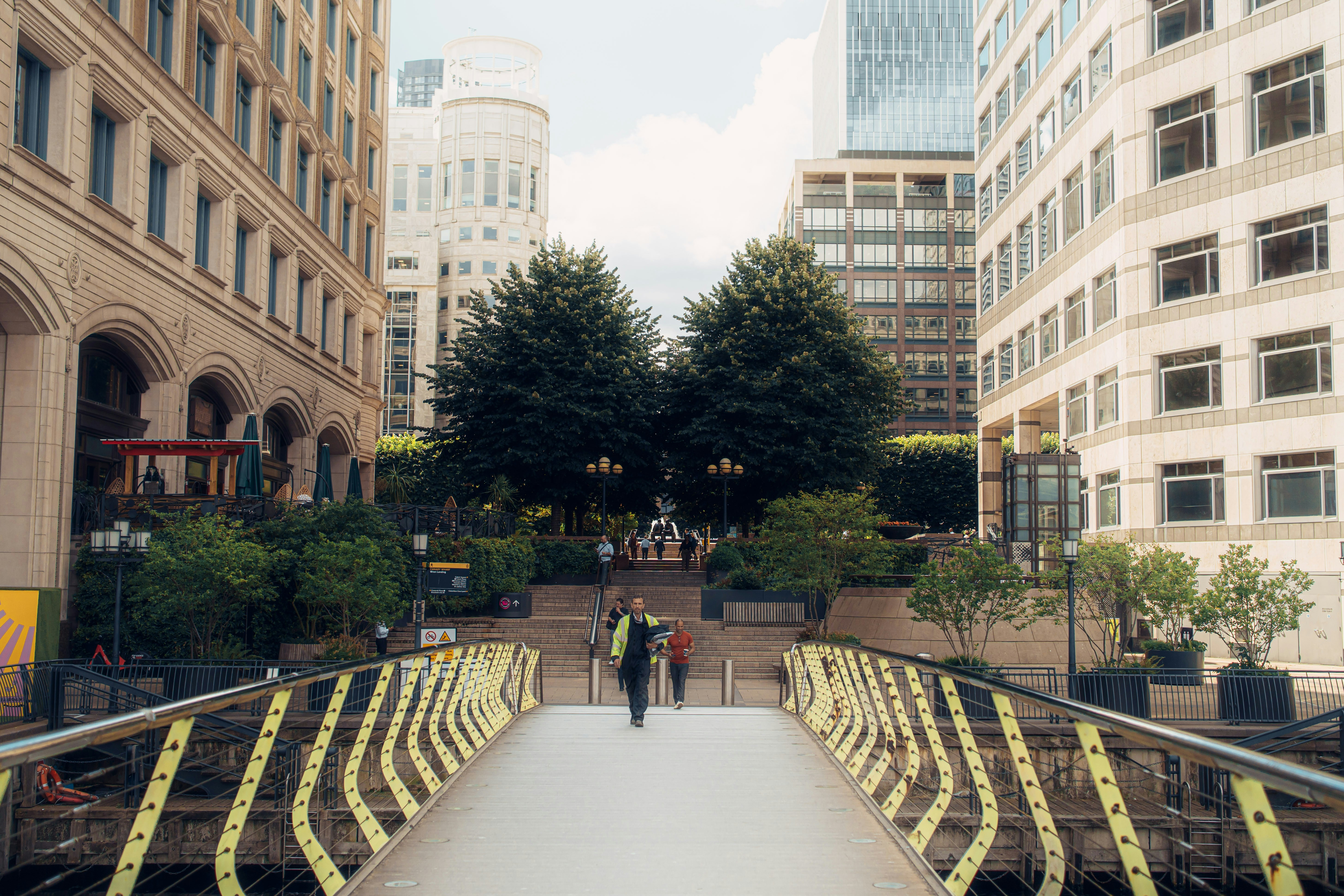 Urban promenade toward a shaded plaza framed by towers
