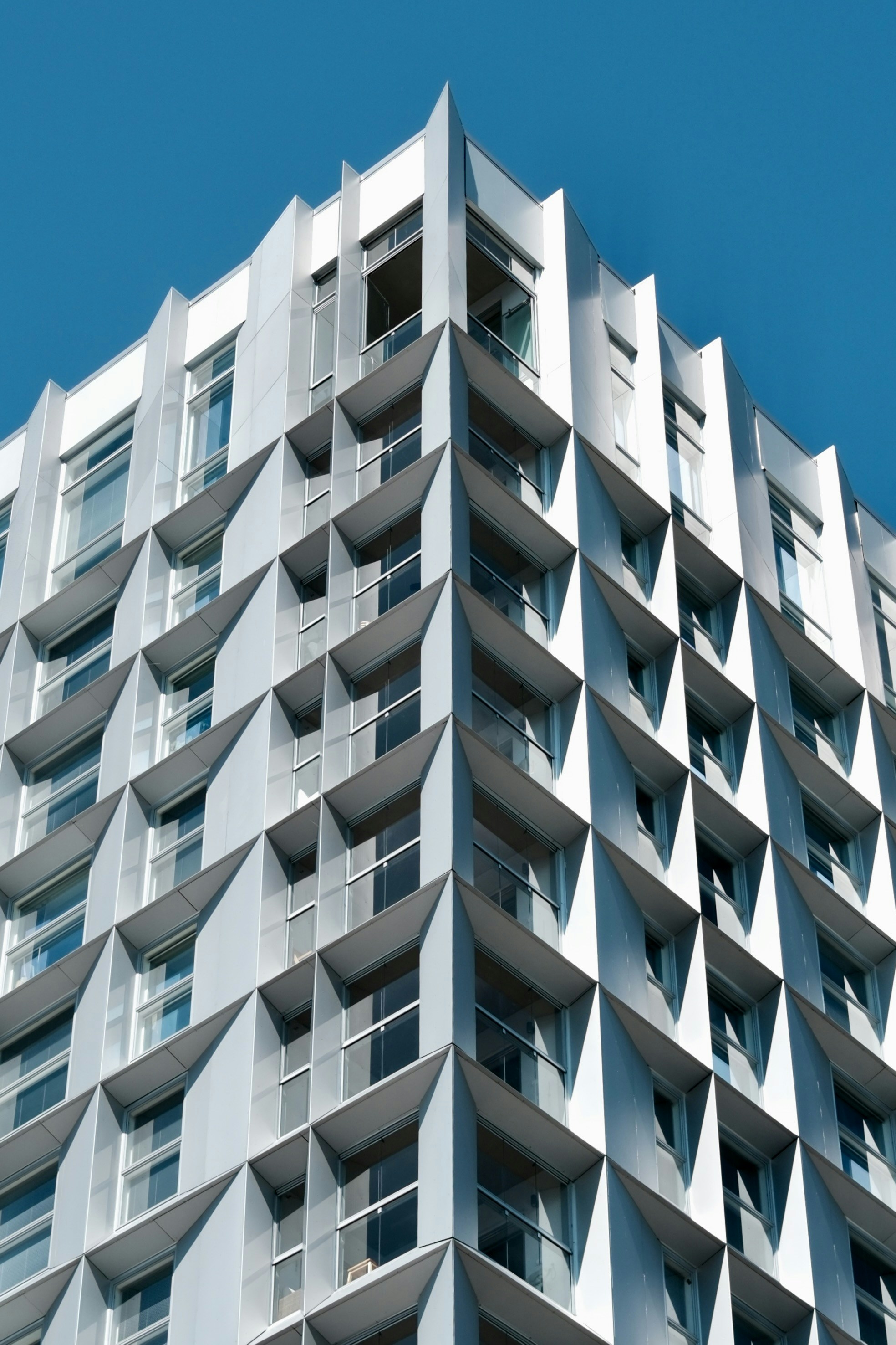 Modern building with geometric facade against a clear blue sky.