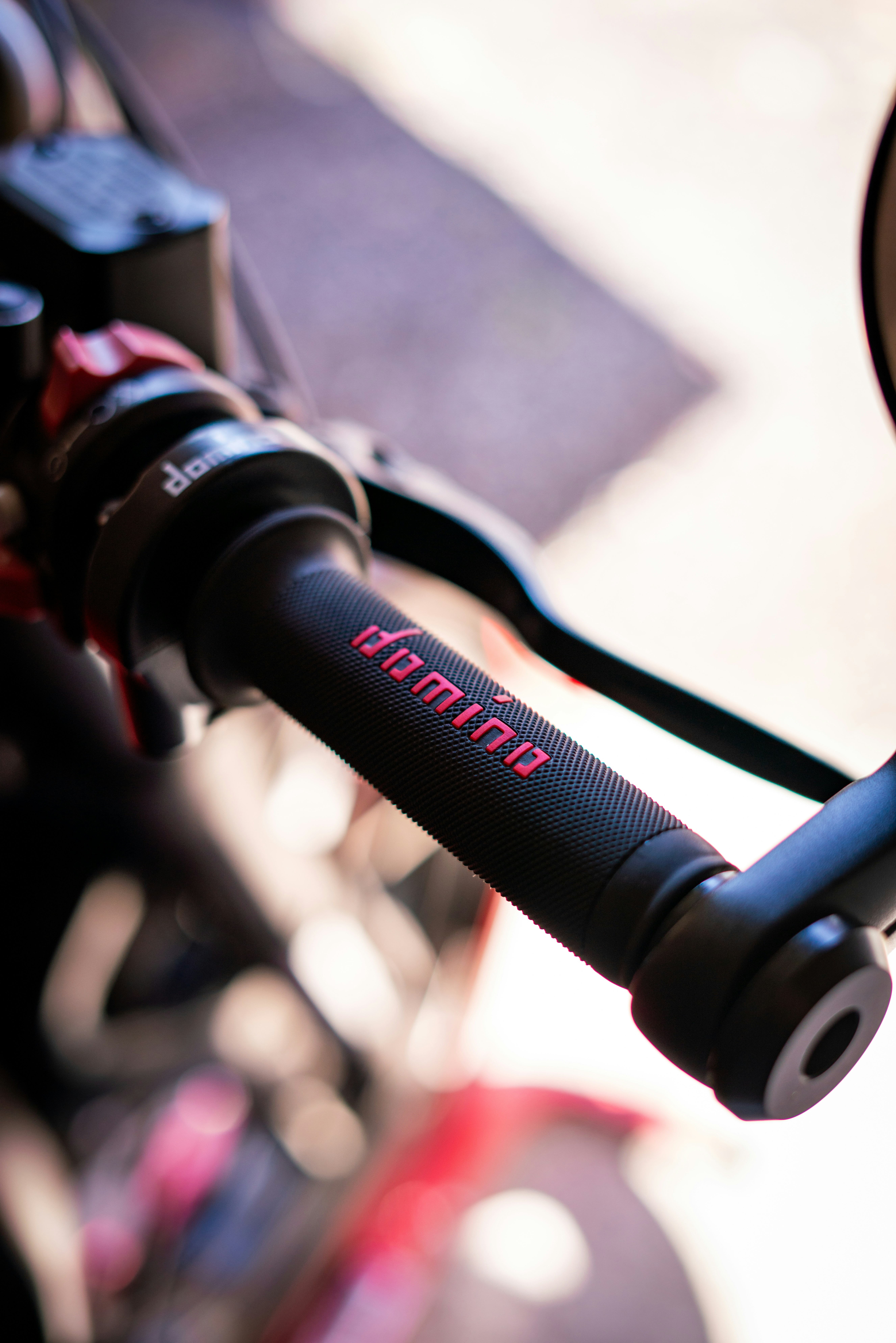 Grip of Focus: The Red Fabric and Textured Bar on a Motorcycle Handlebar