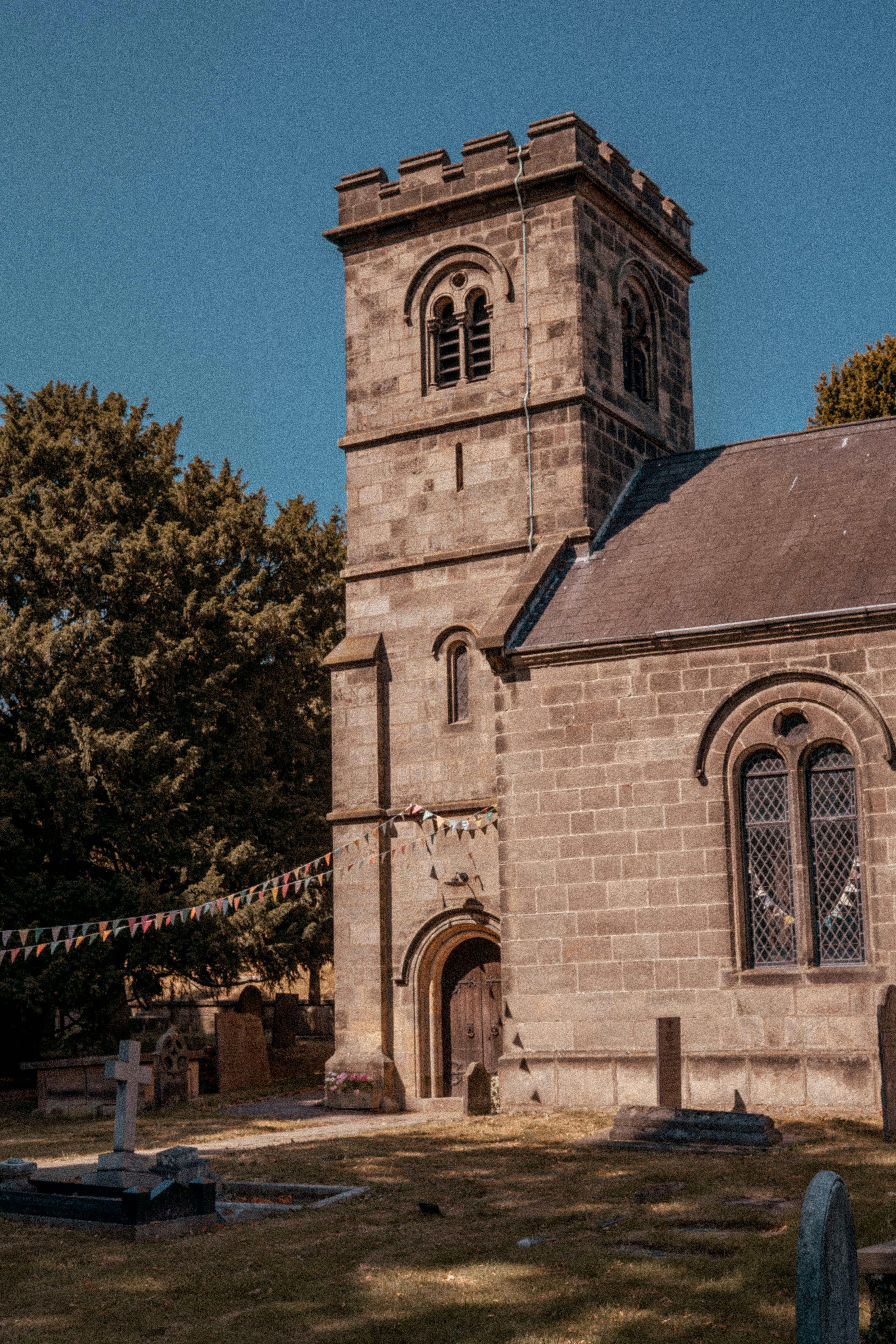 Stone church with ivy-shadowed graveyard under a clear blue sky