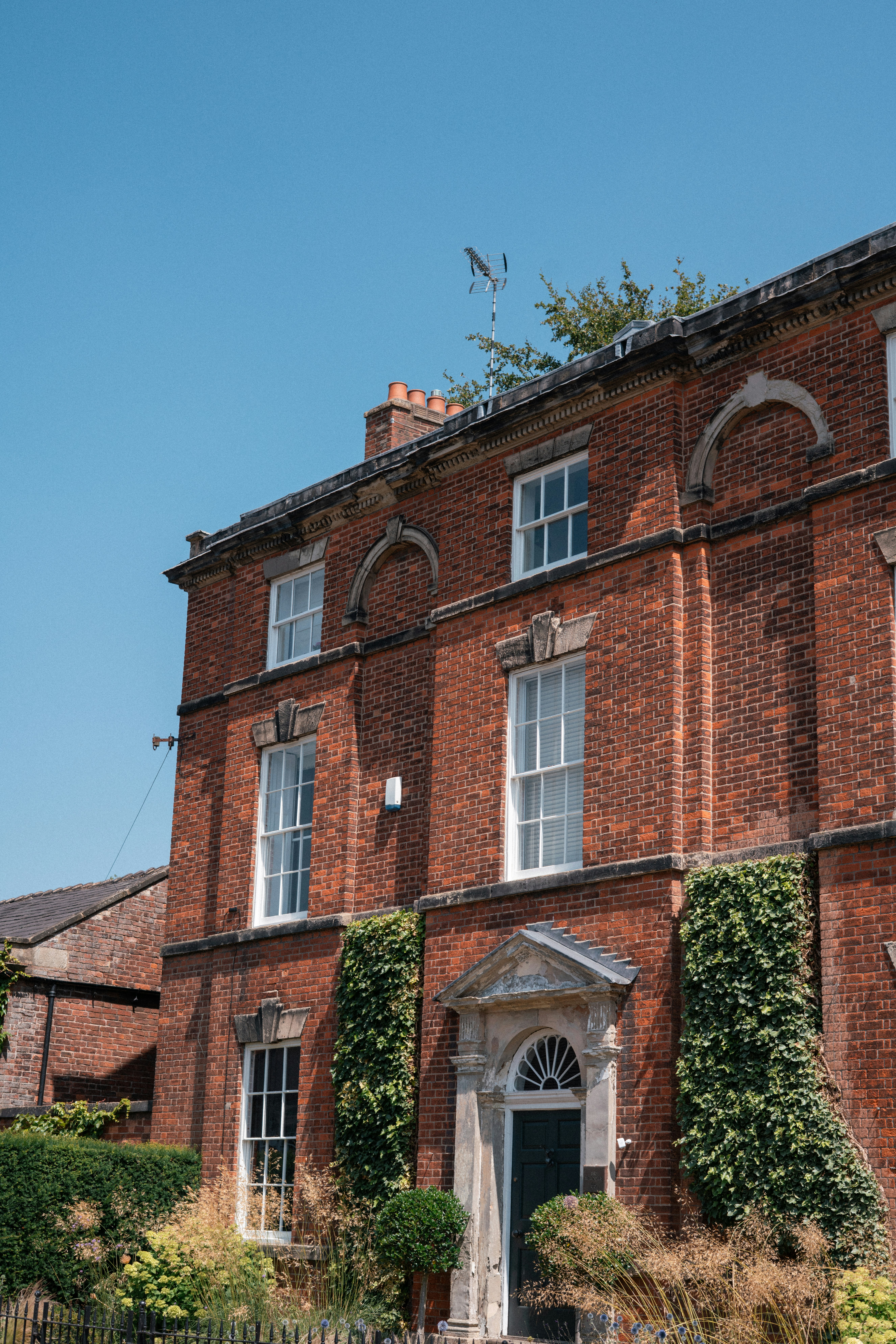 Brick Facade of Ivy-Clad Manor Under Clear Summer Sky