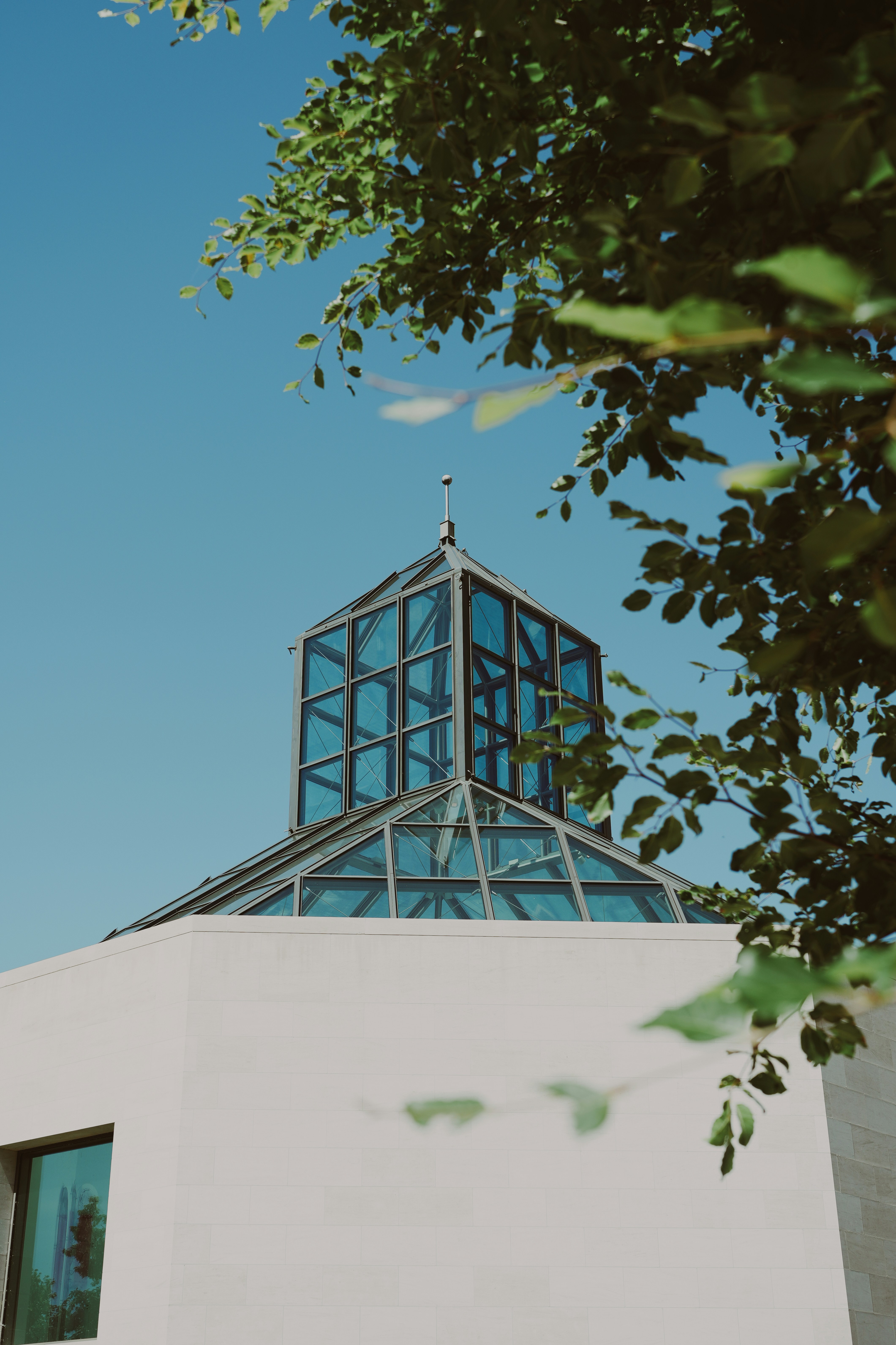 Glass-roofed architectural peak above a sunlit white facade