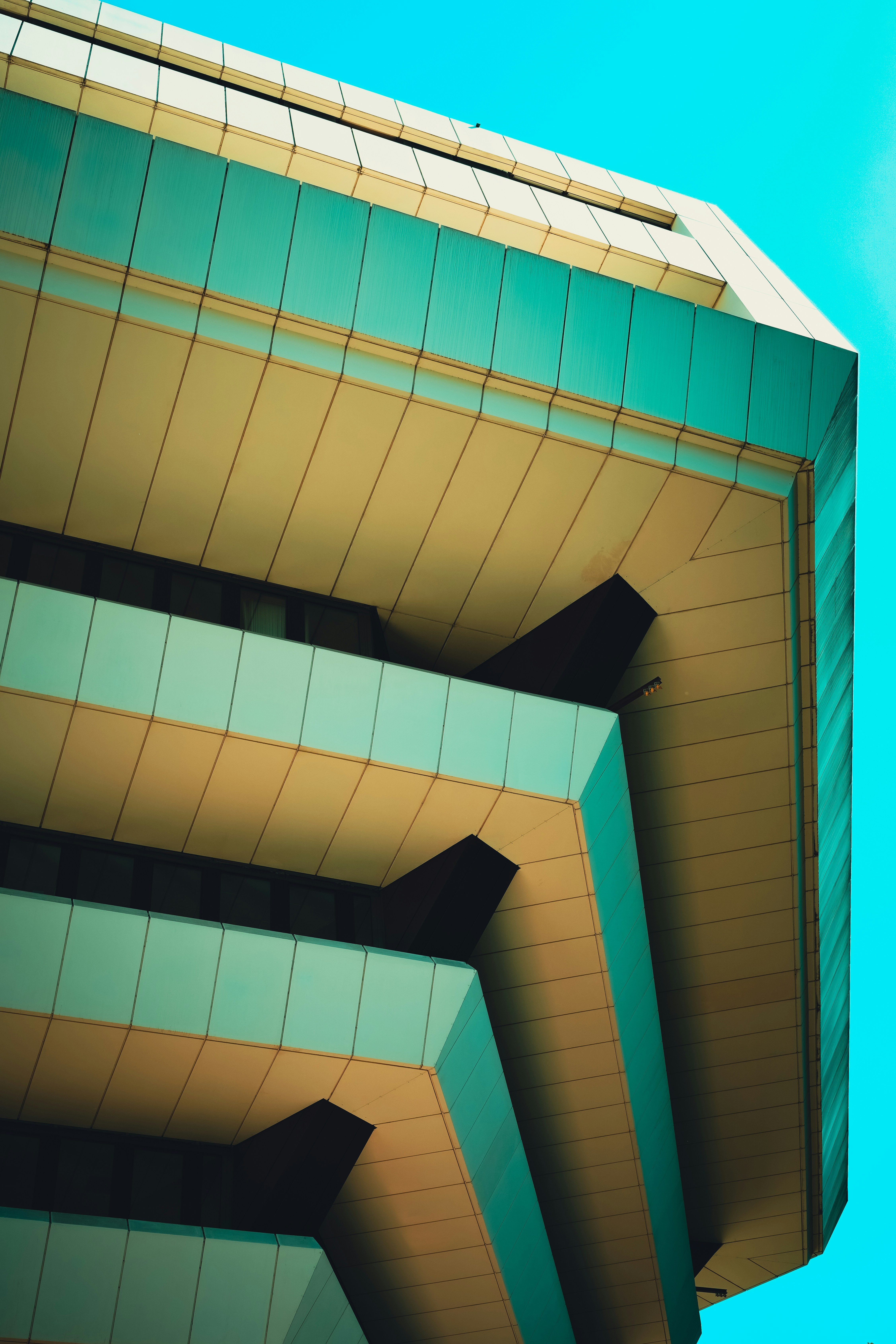 Concentric Angular Facade: Recurring Tiers Reaching Toward a Cyan Sky