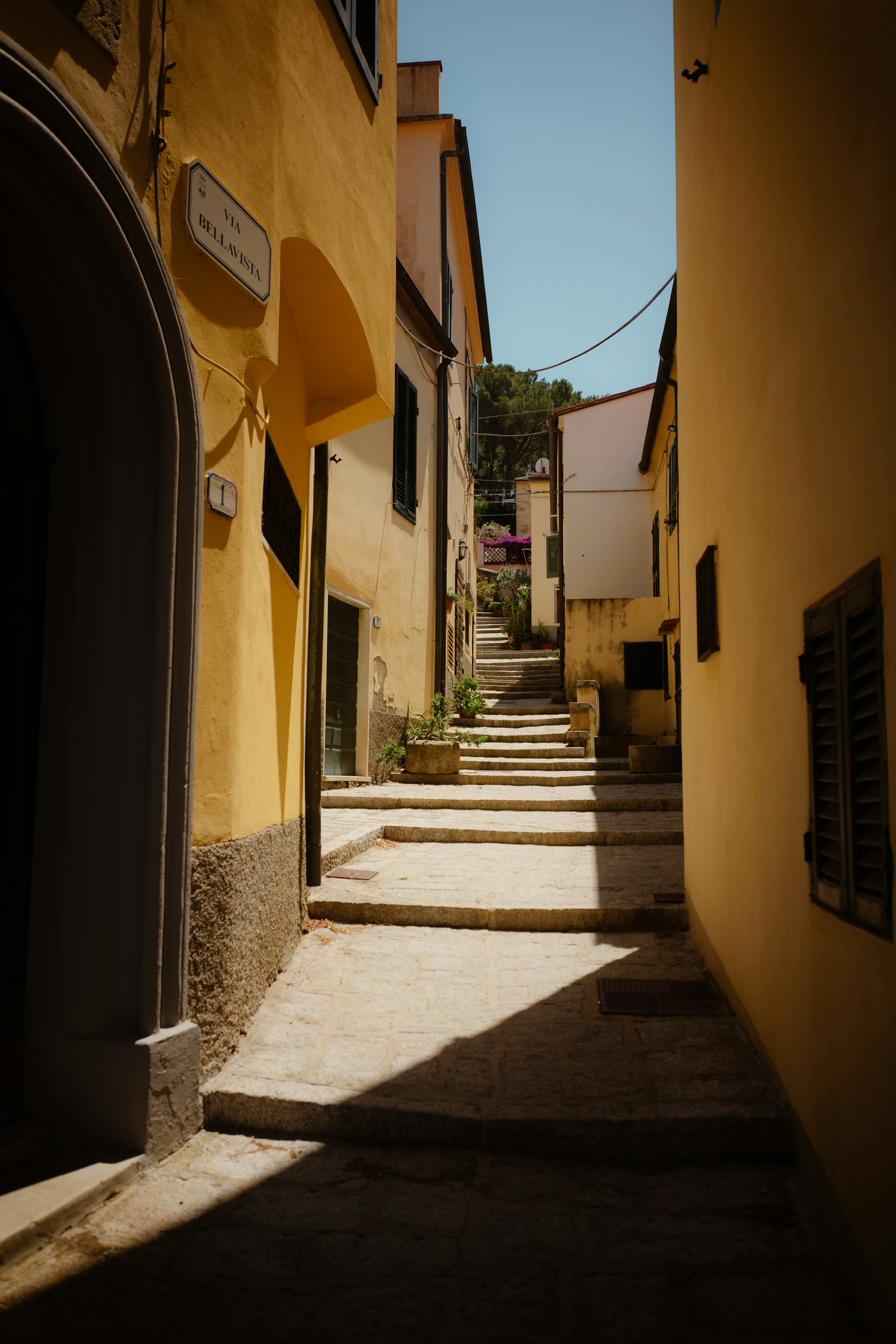 Sunlit Passage: A Narrow Staircase Between Warm Yellow Walls