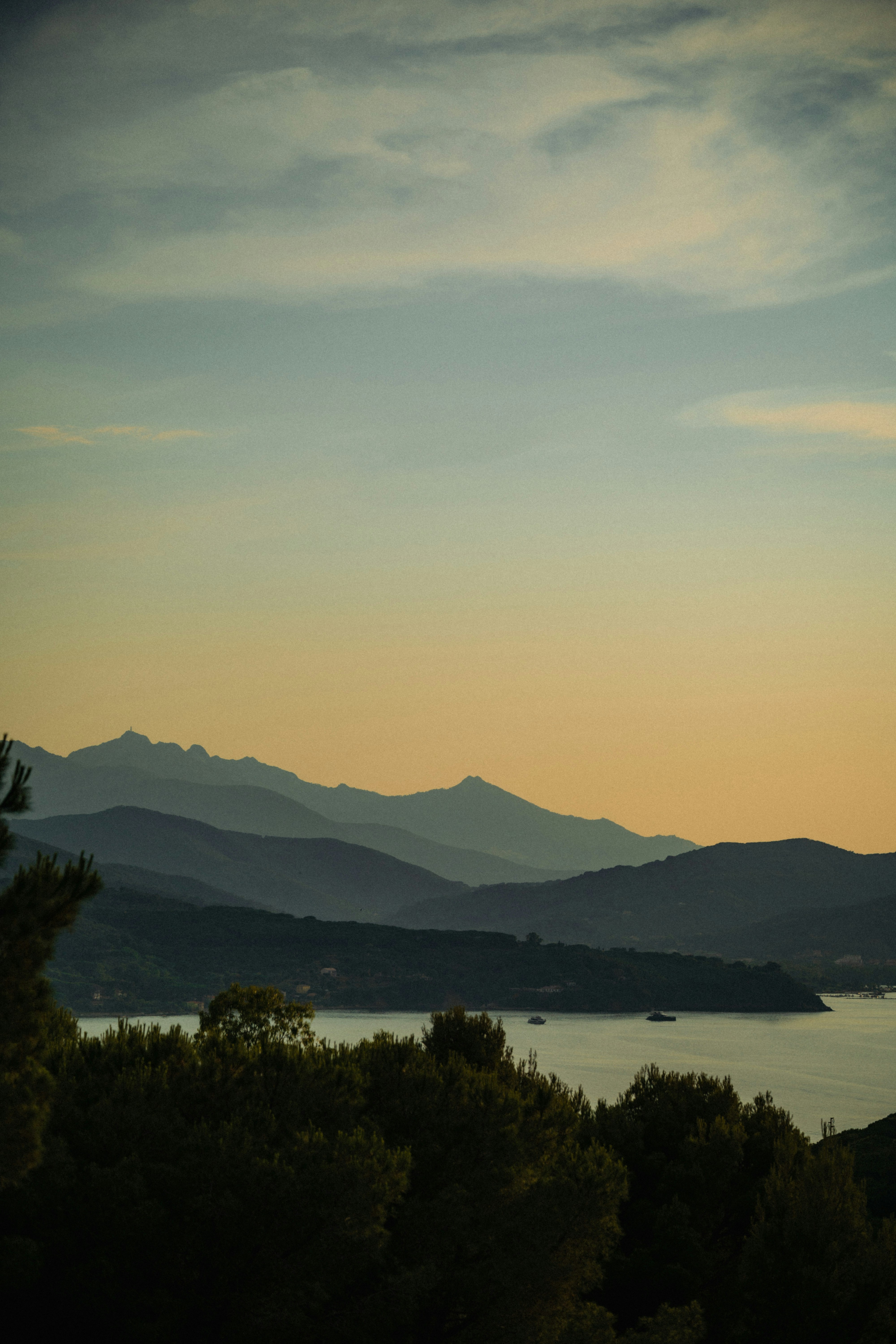 Golden Range: Silhouetted Peaks at Dusk Over Serene Bay