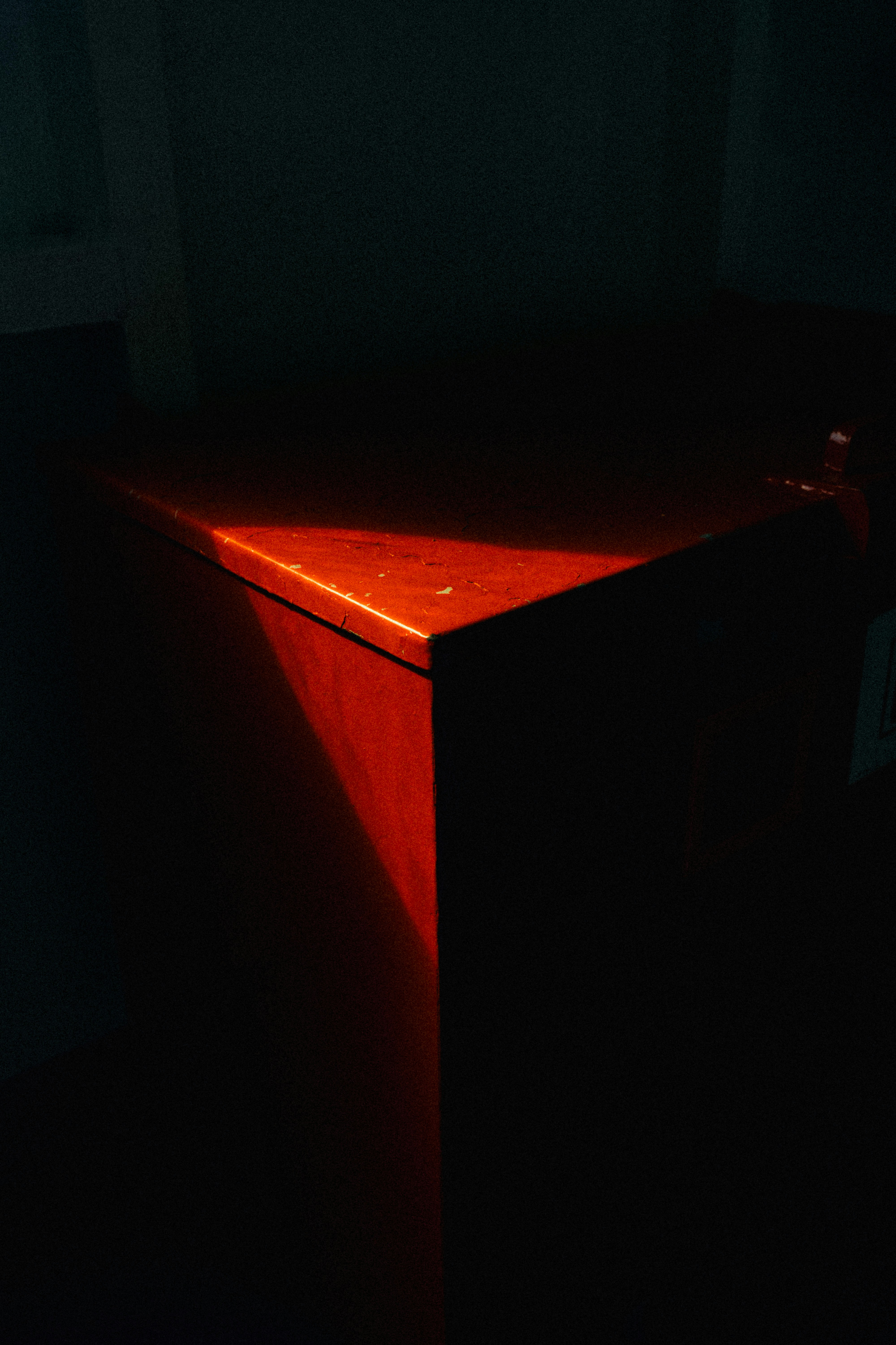 A Dim Red Highlight: Edge of a Wooden Cabinet in Low Light