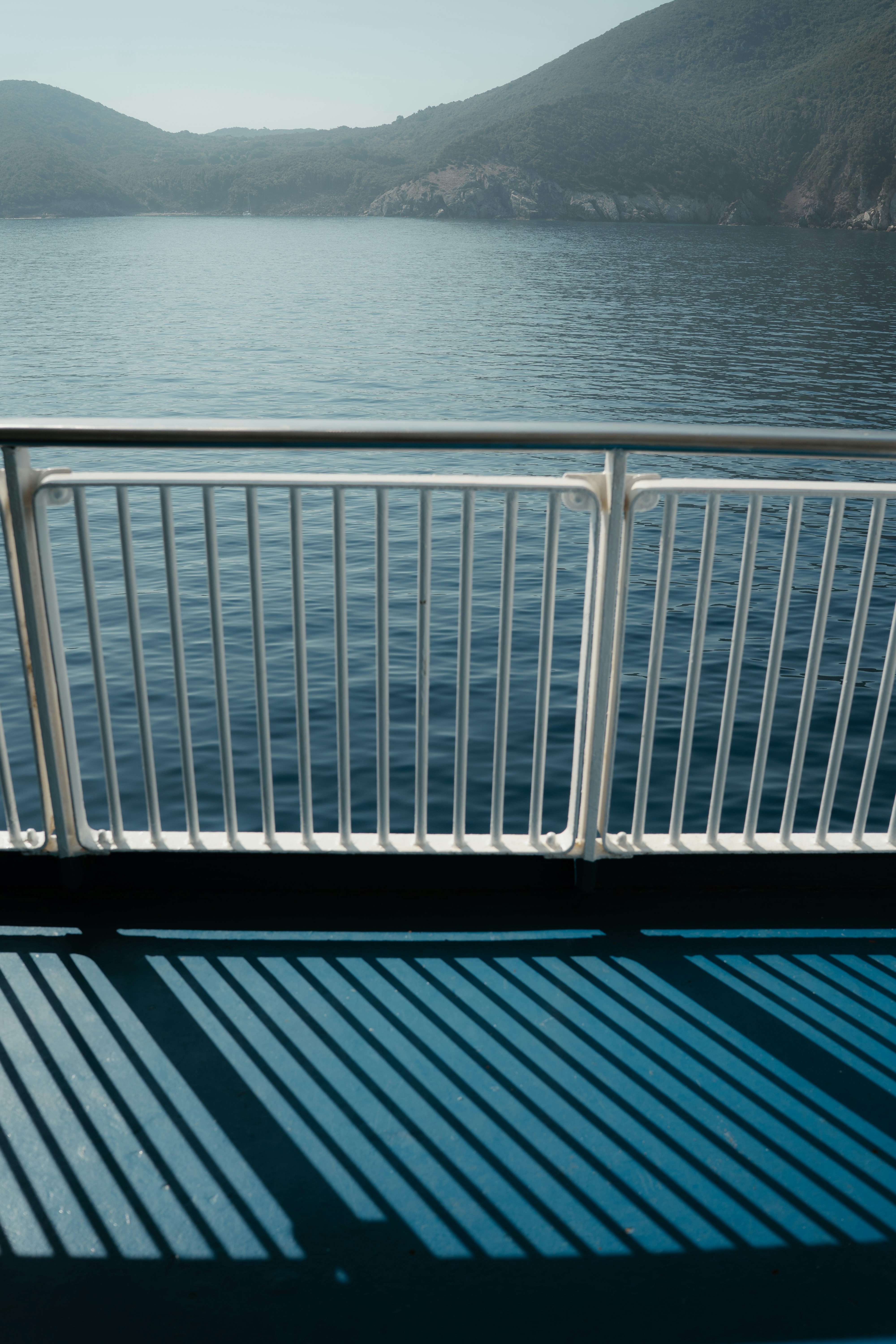 Sunlit Deck Railing Over Calm Harbour