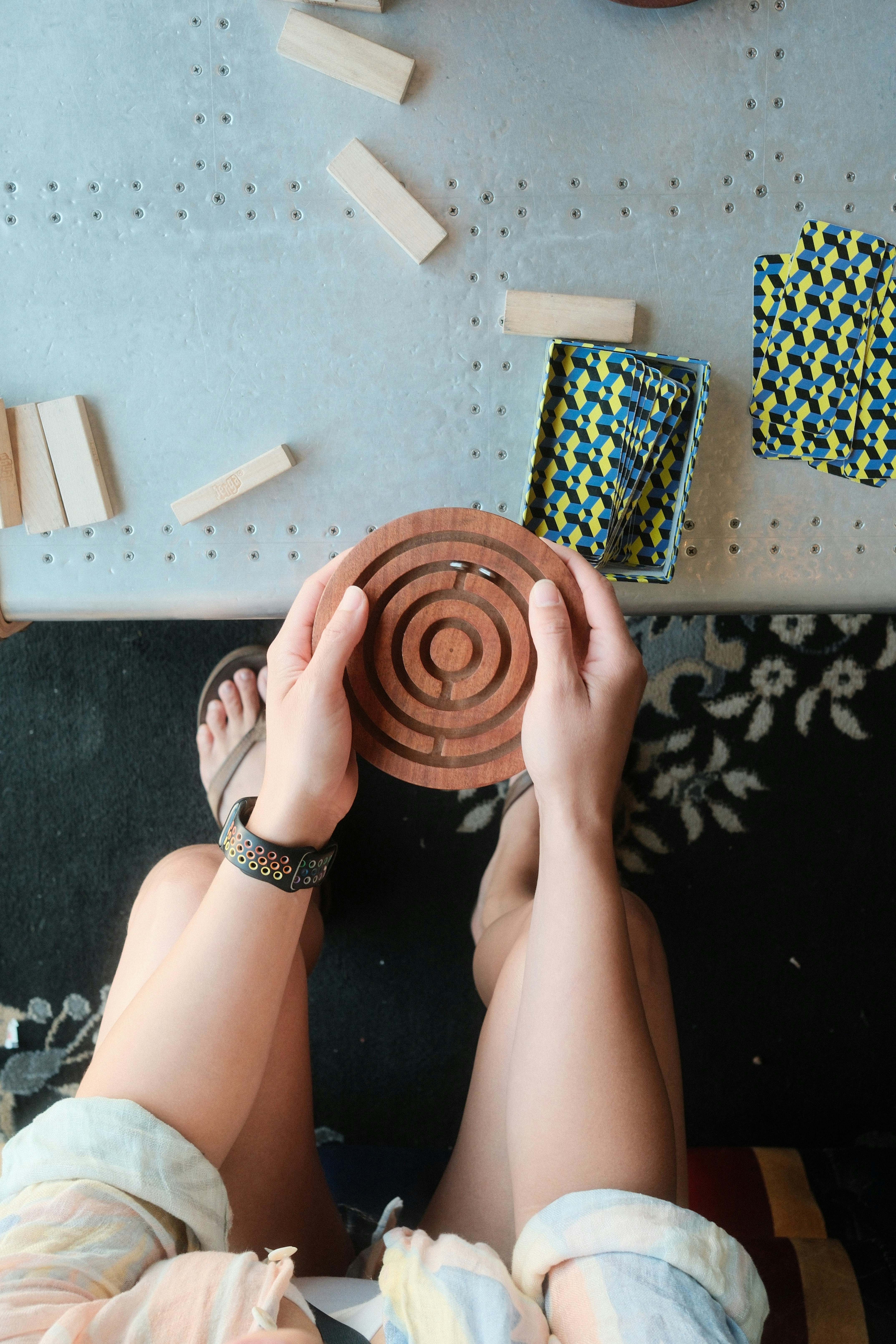 Circular wooden spun pattern cradled in a pair of hands over a game table