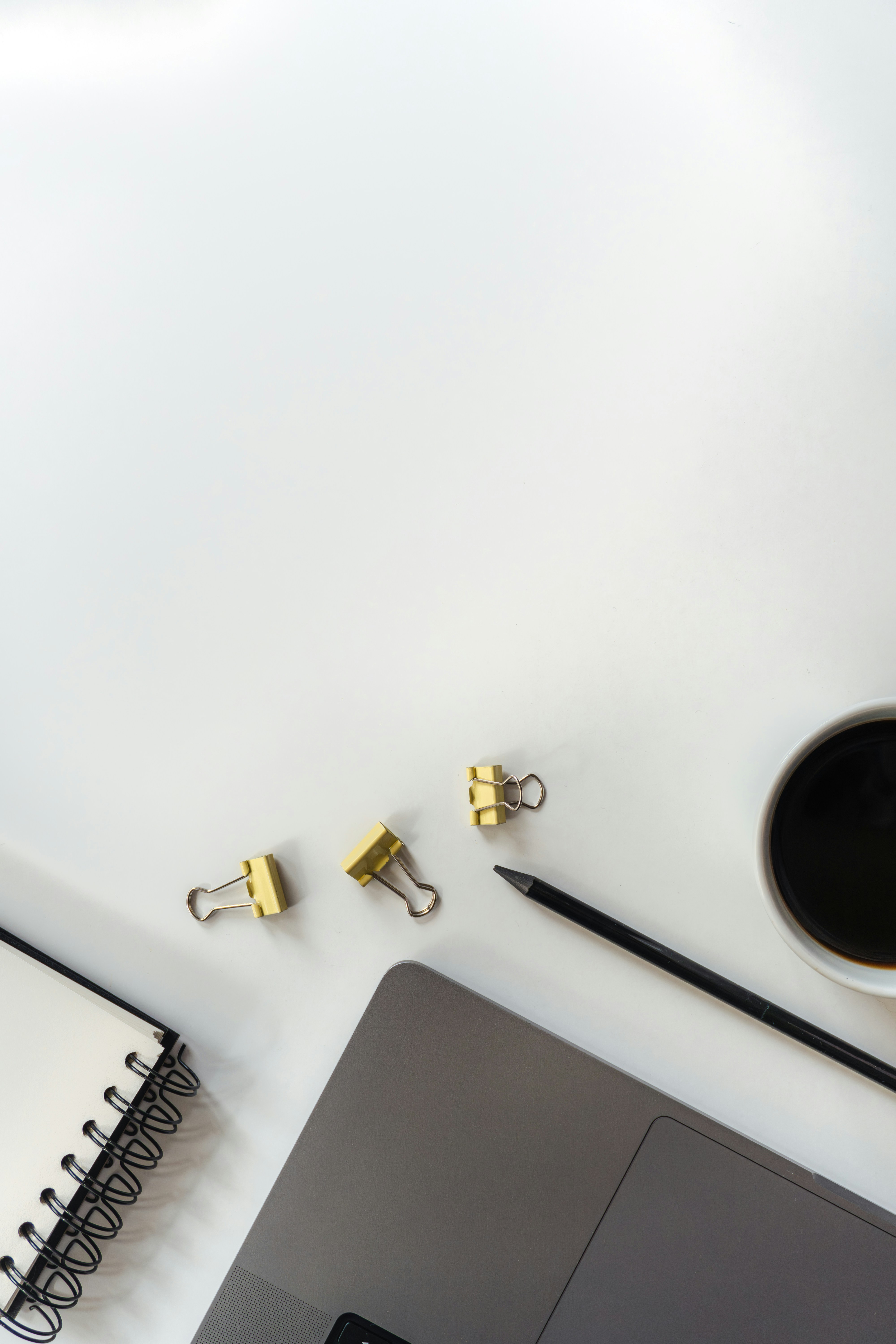 Desk Essentials in Clean Light: Coffee, Laptop, and Golden Clips