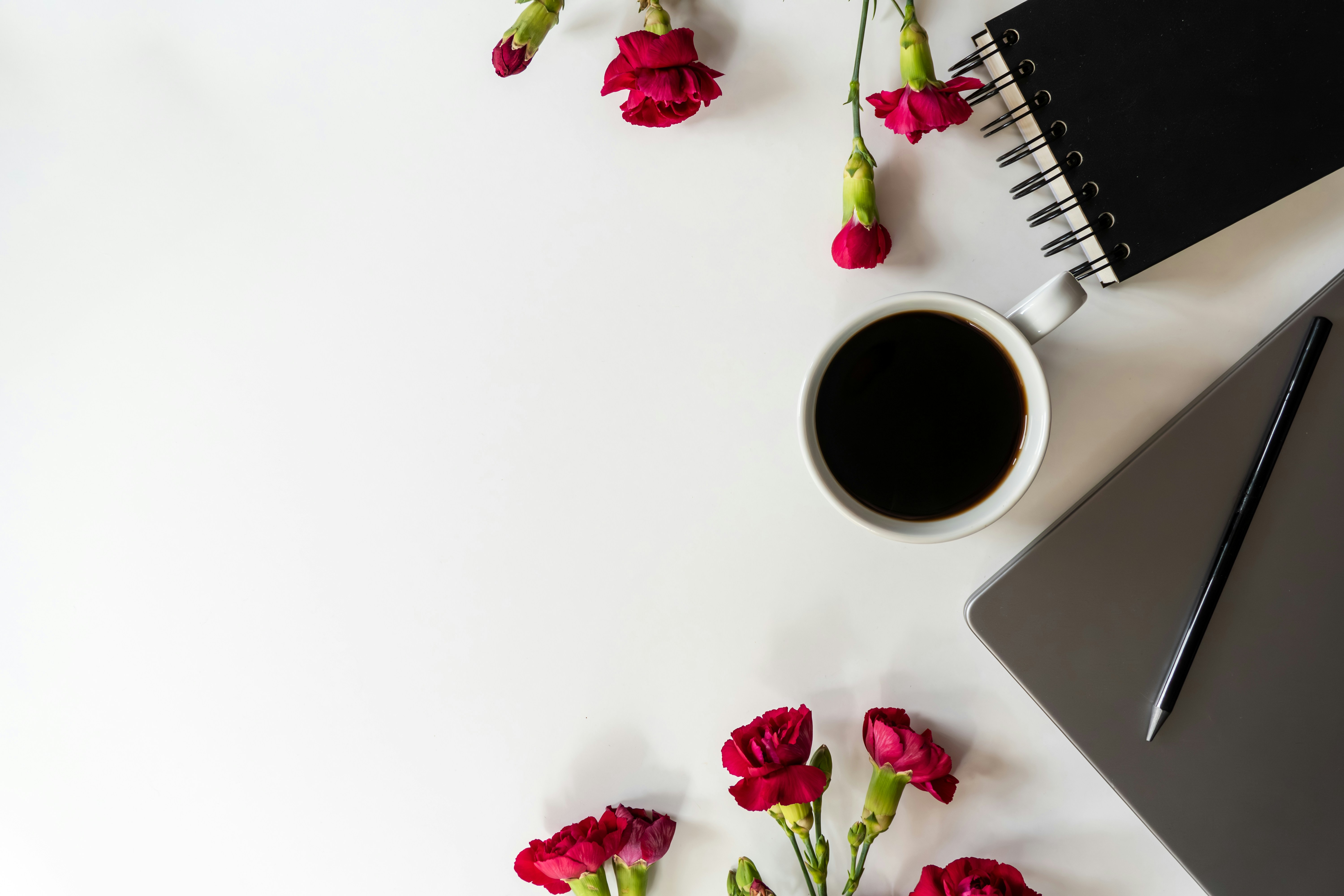Minimalist desk with coffee and red carnations
