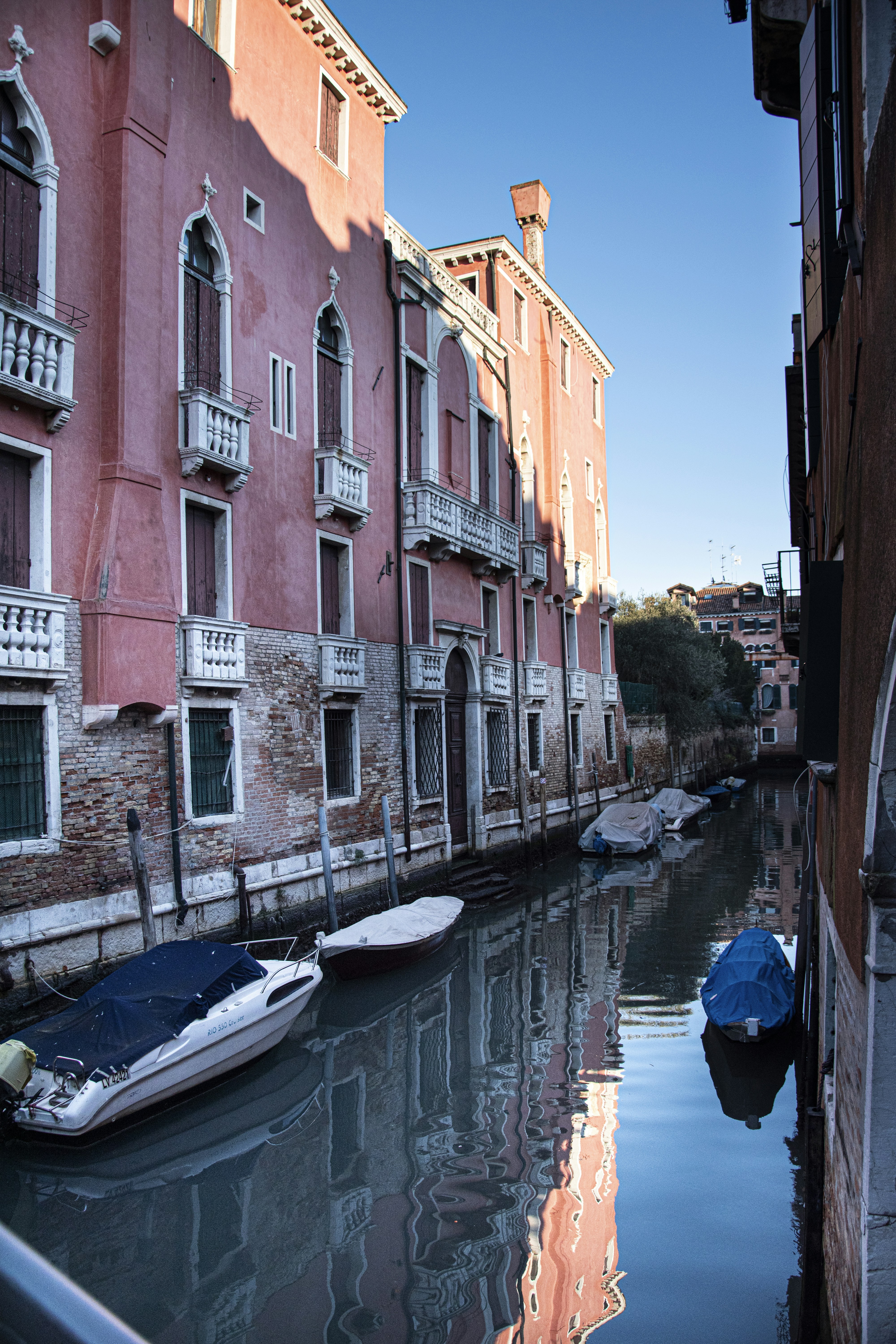 Venetian Canal Facade: Coral Building Reflects in Quiet Waters