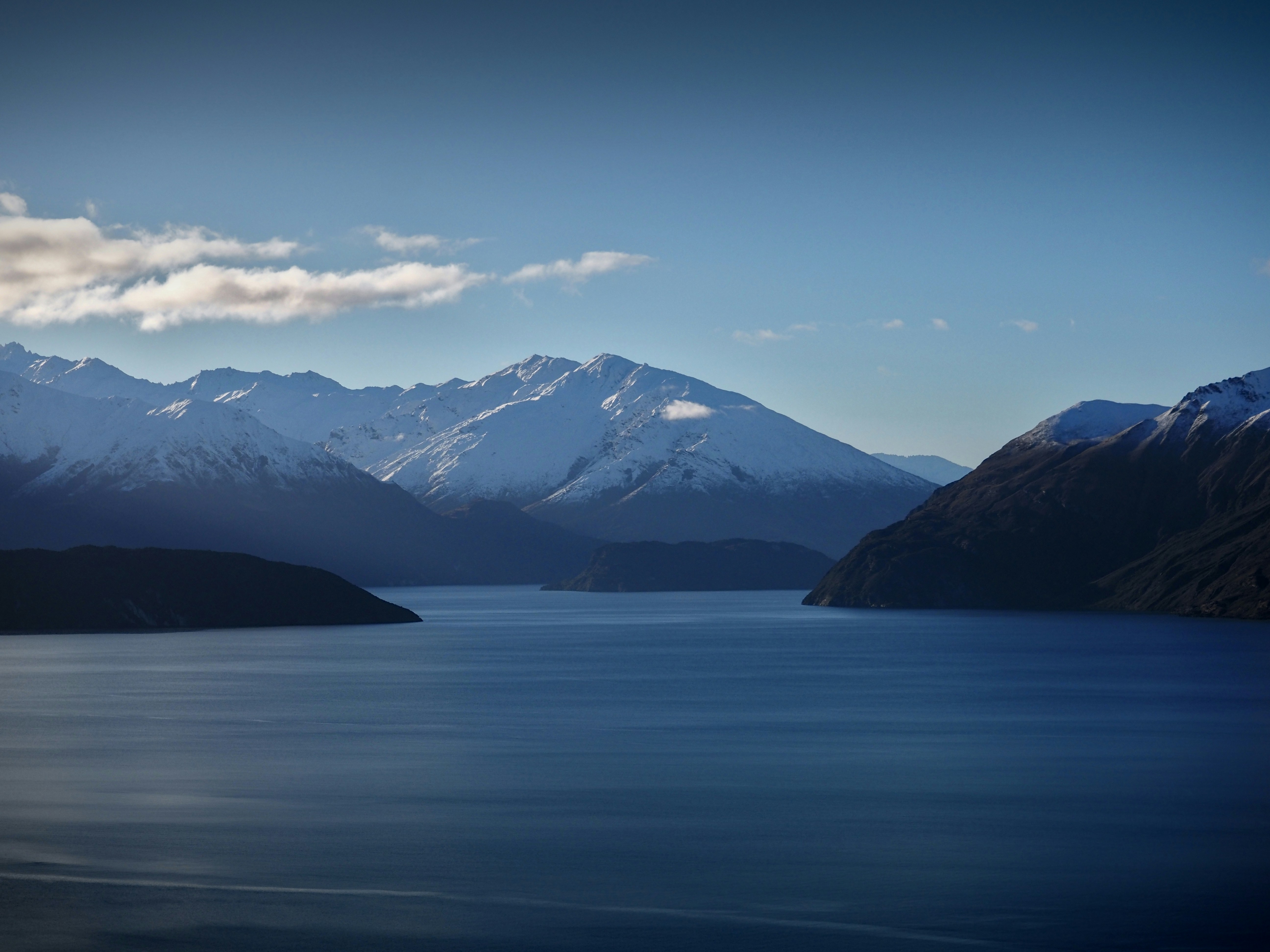 Midday Fjord: Snow-capped Peaks Reaching Over a Tranquil Blue Inlet
