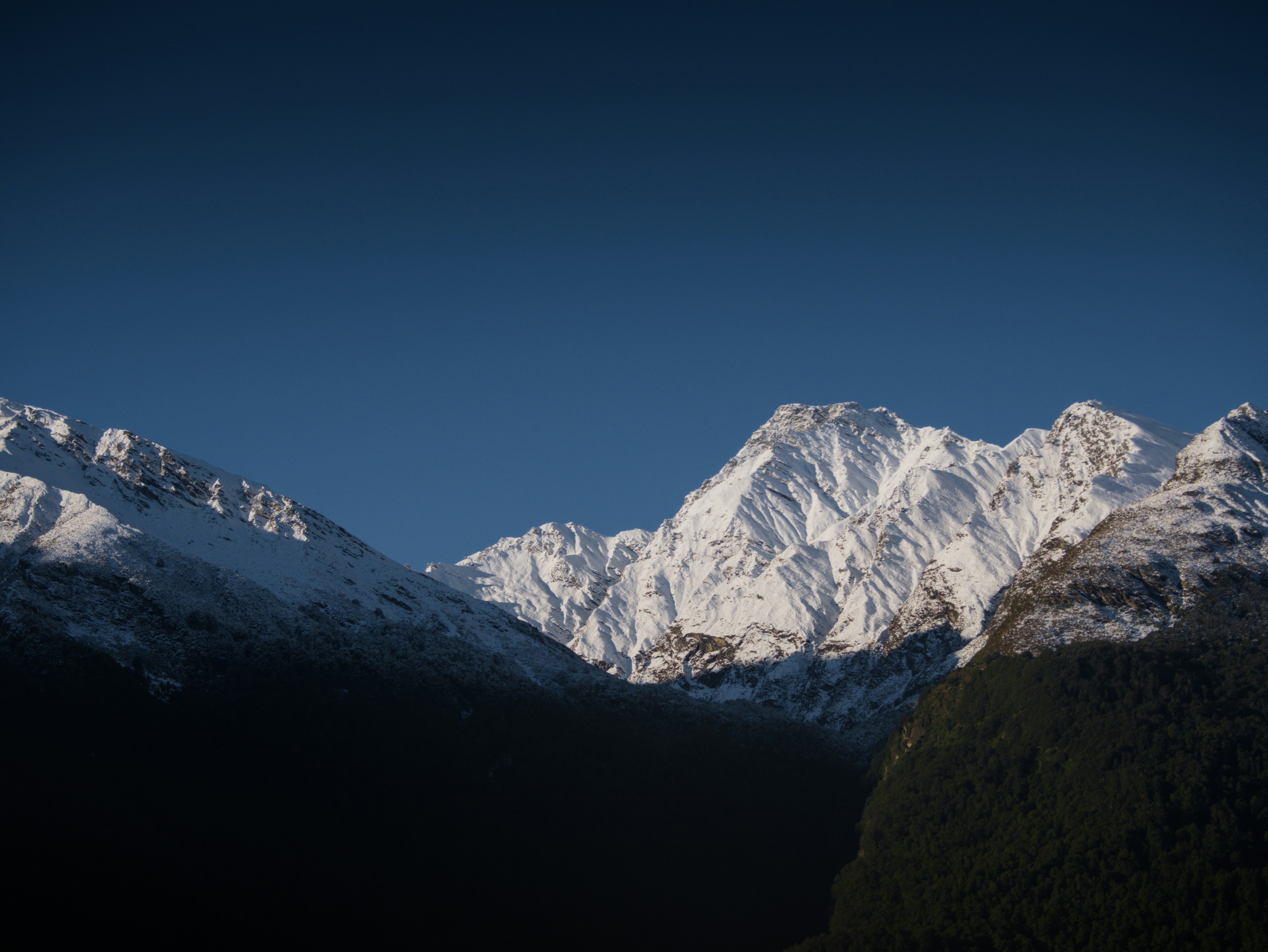 Sunlit Spine: Snow-Crowned Peaks Against a Midnight Sky