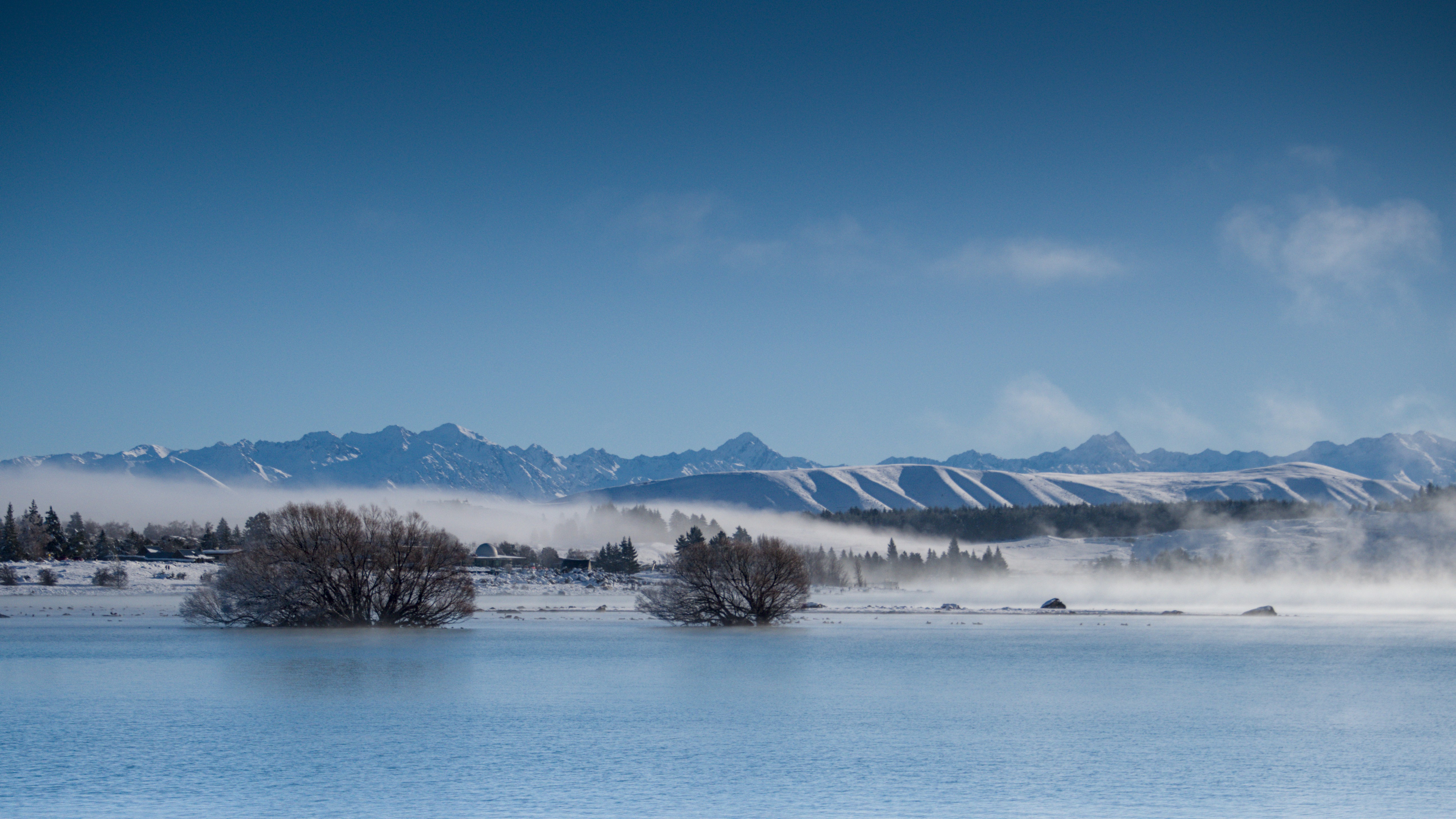 Mist over a Snow-Dusted Lake Beneath a Terraced Mountain Range