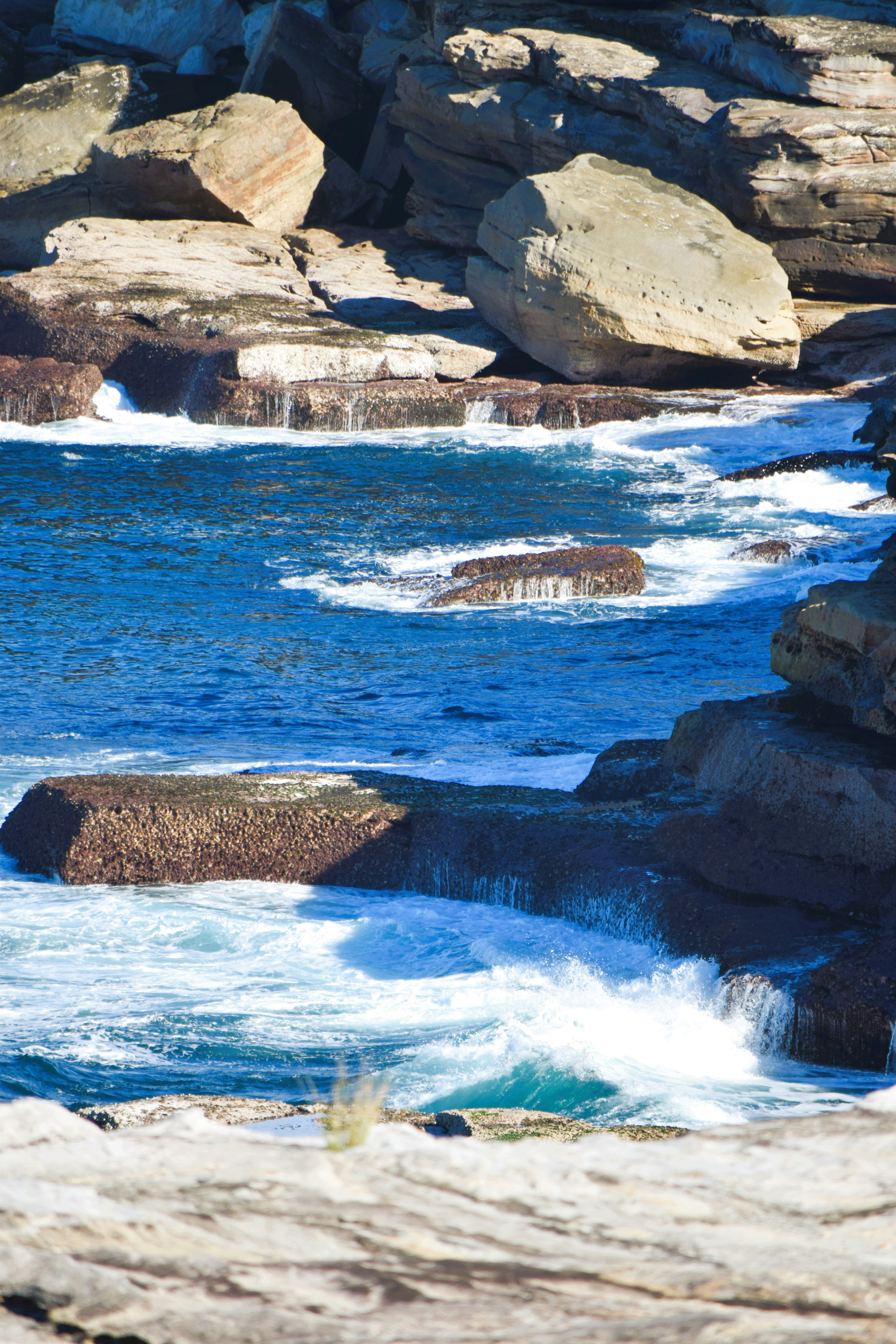 Coastal Cathedral: Sunlit Rocks Meet Turquoise Surge