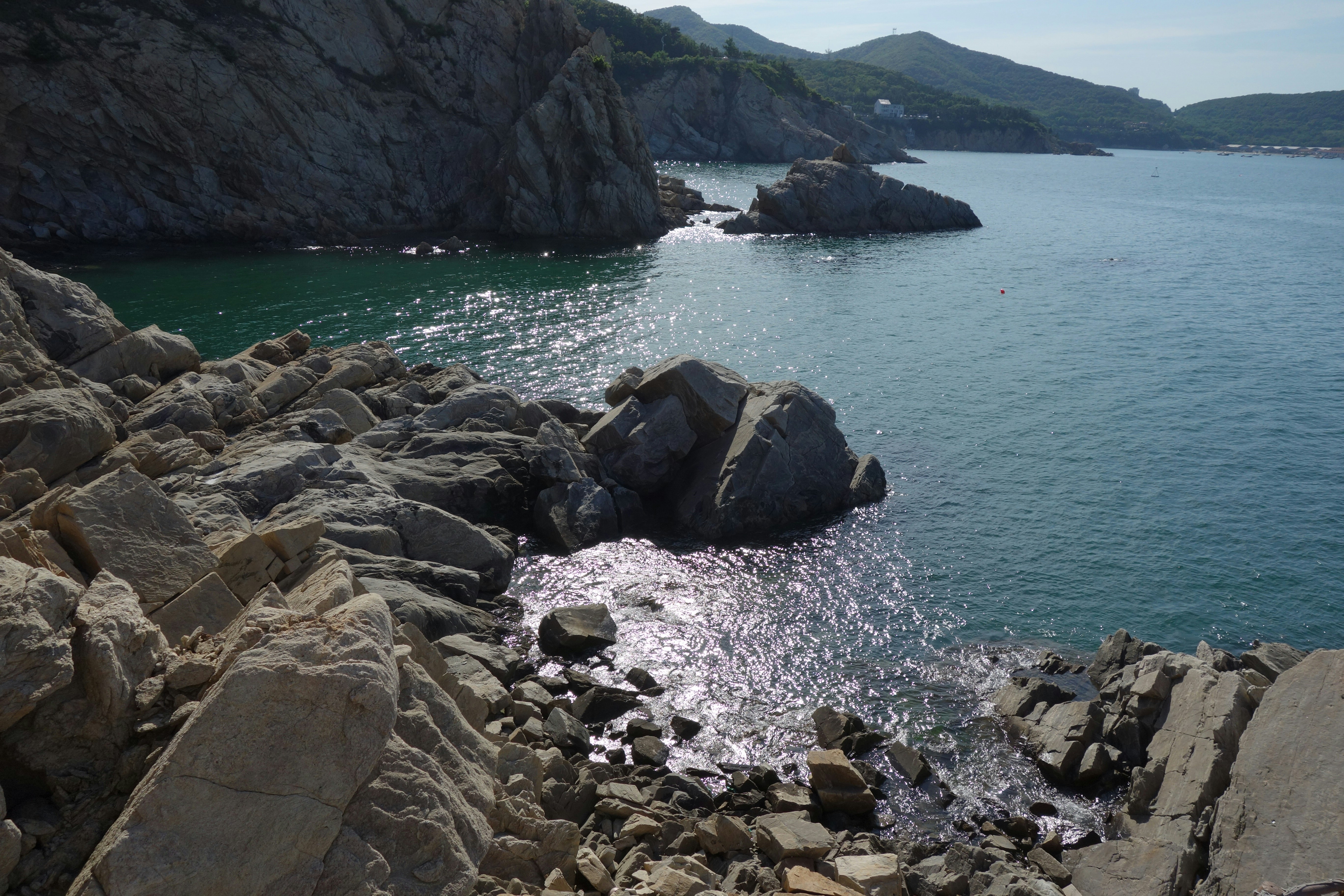 Sunlit Cobble Shore: Quiet Seascape Along Rugged Rocks