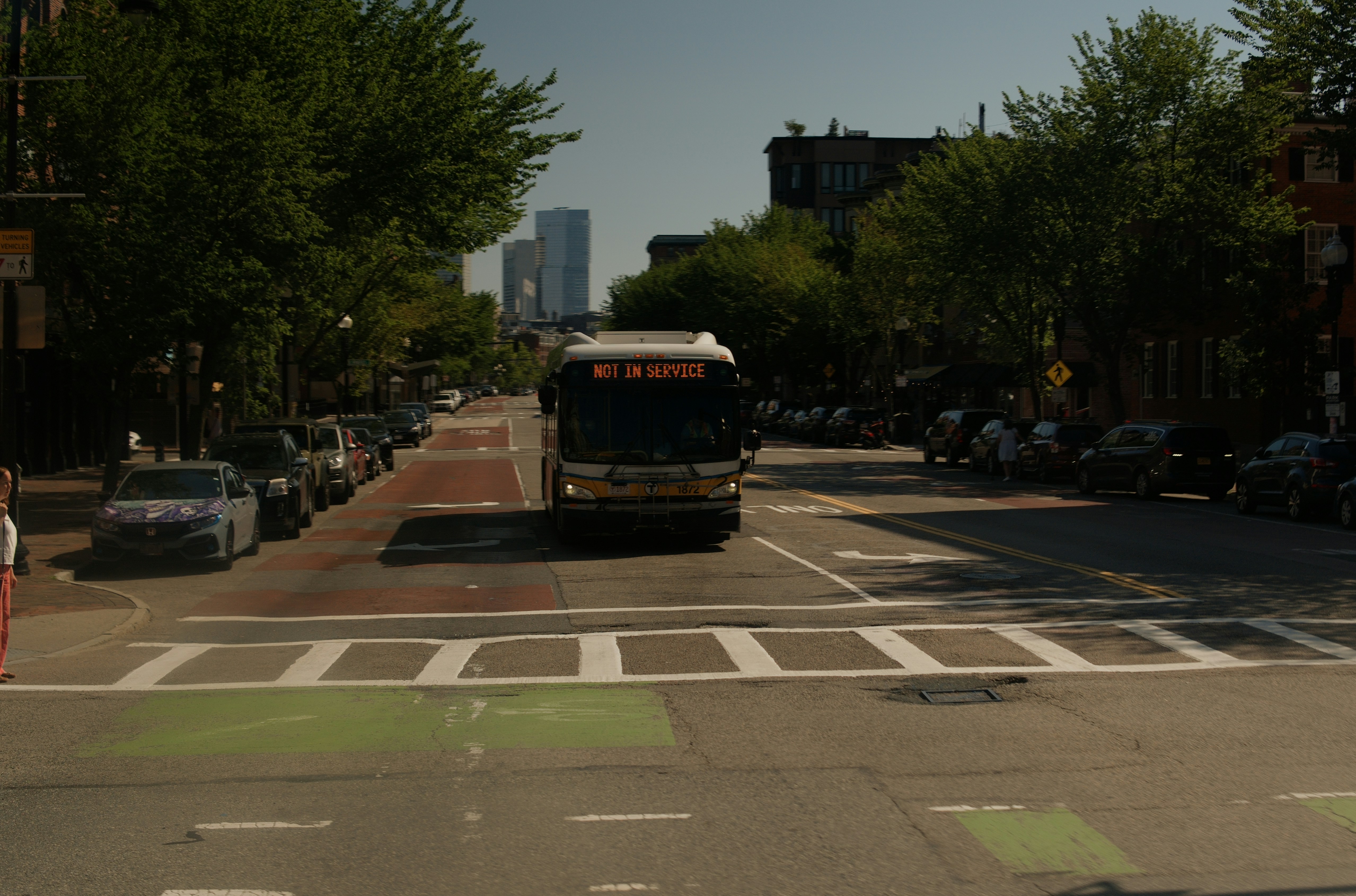 Bus on a Quiet City Street Aiming Toward Distant Skyline
