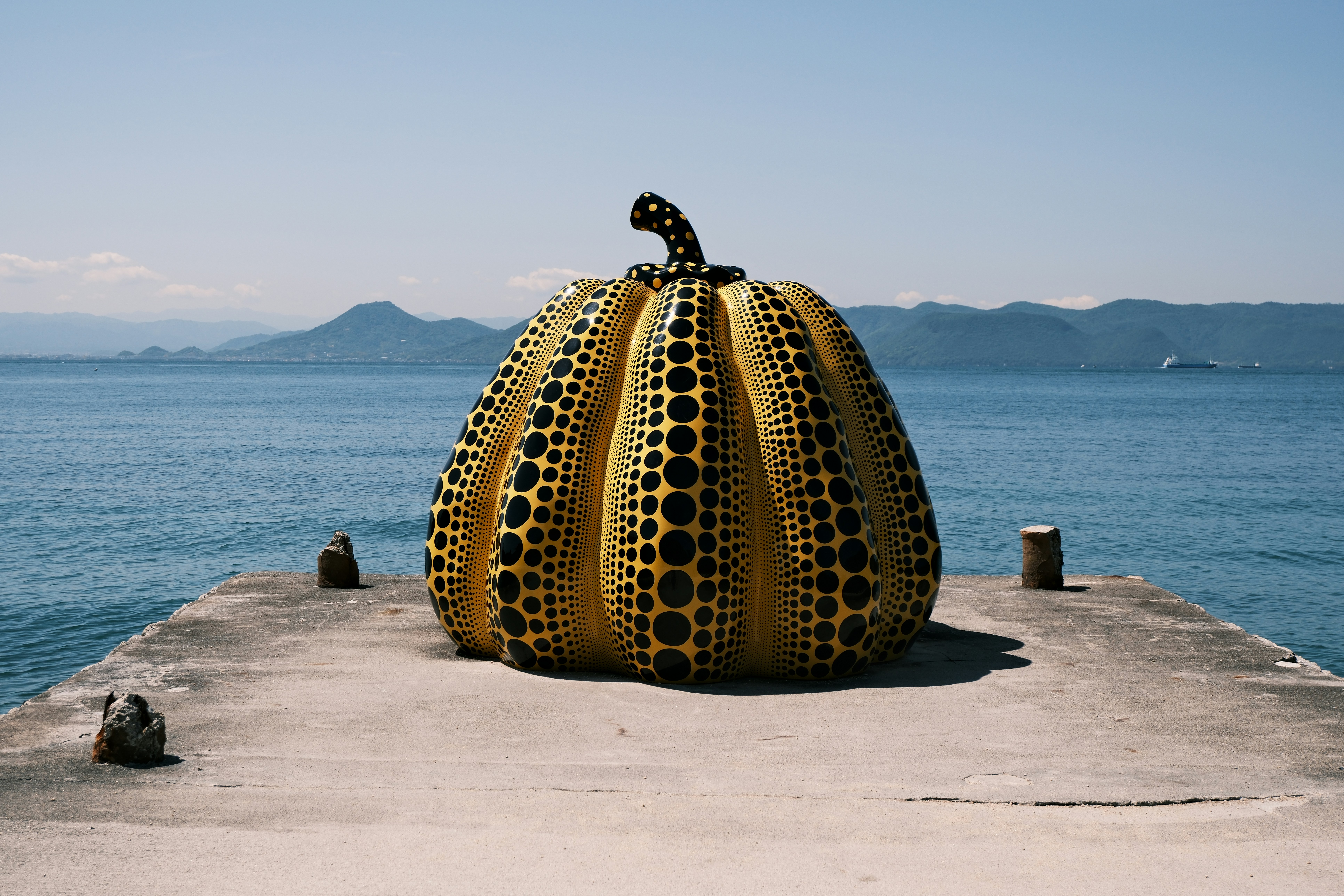 Golden Gulliver: a solitary golden pumpkin on a pier with a blue sea
