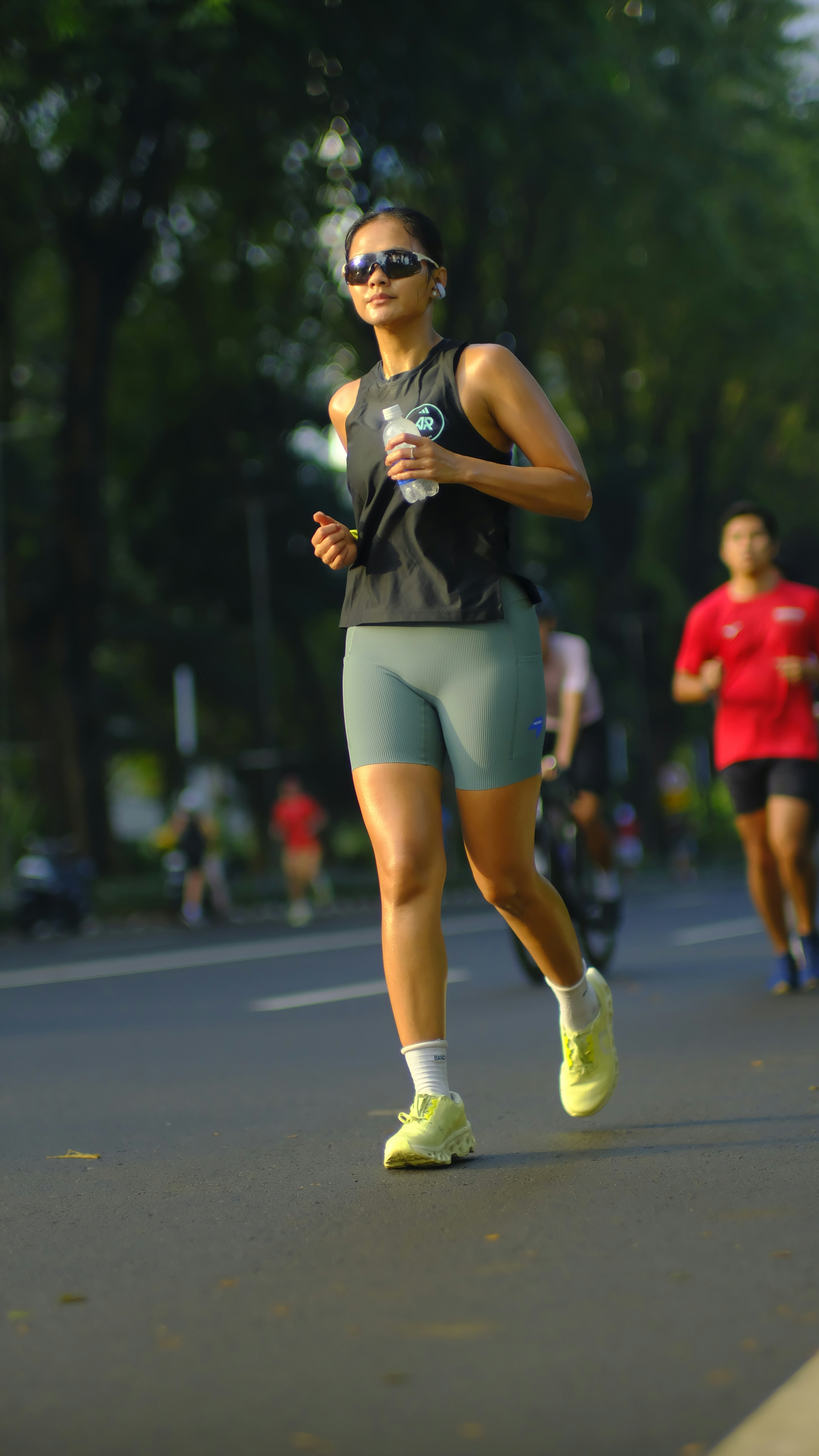 Runner in Sunglasses Carries a Bottle Through a Parked-Out Crowd