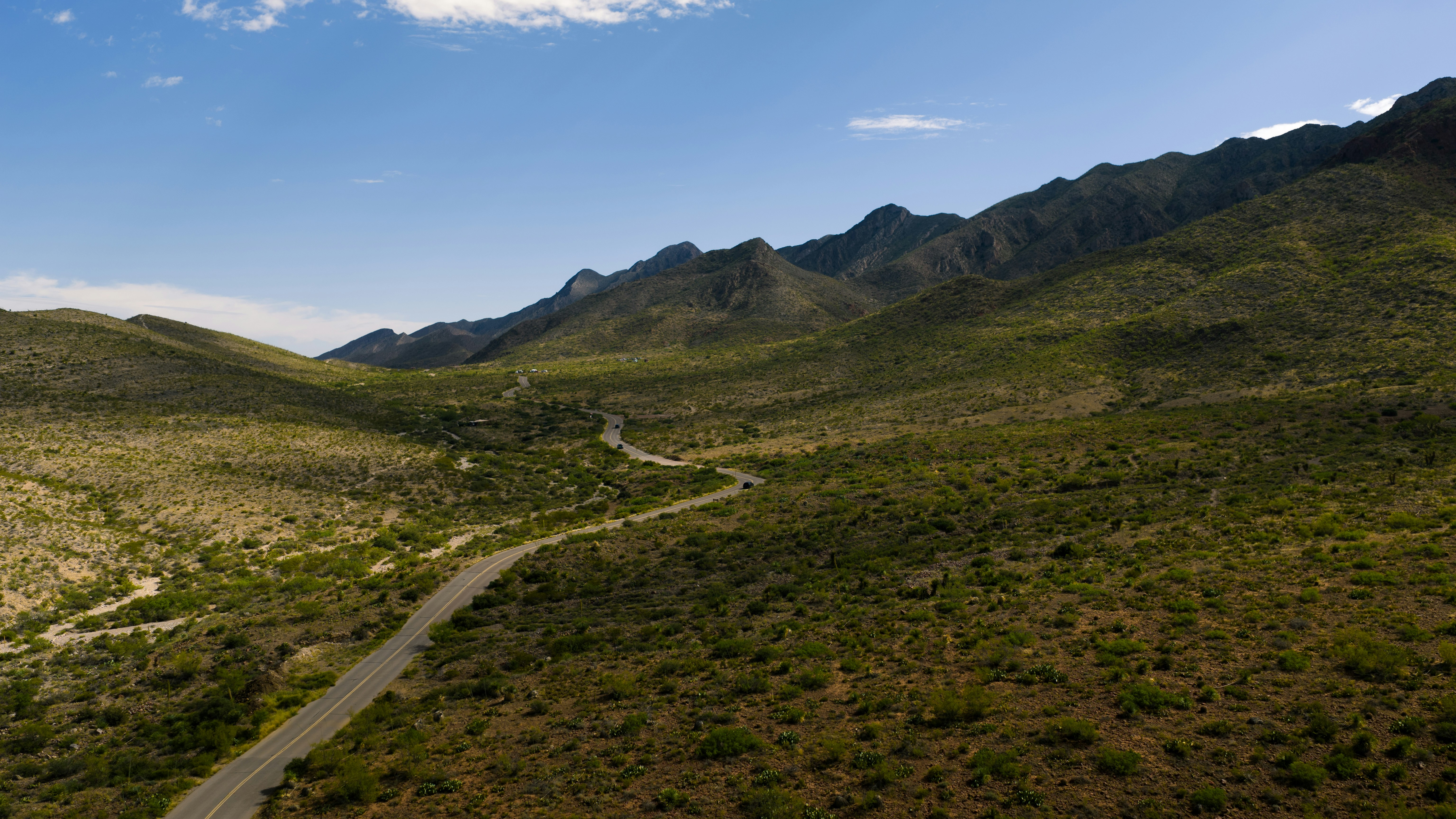 Winding Desert Road Through Stony Hills Under a Wide Blue Sky